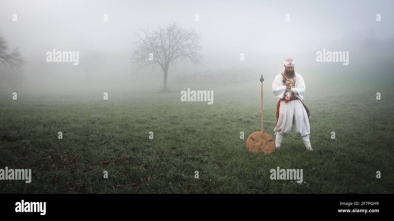 Man is standing in traditional japanese shugendo outfit on green meadow ...