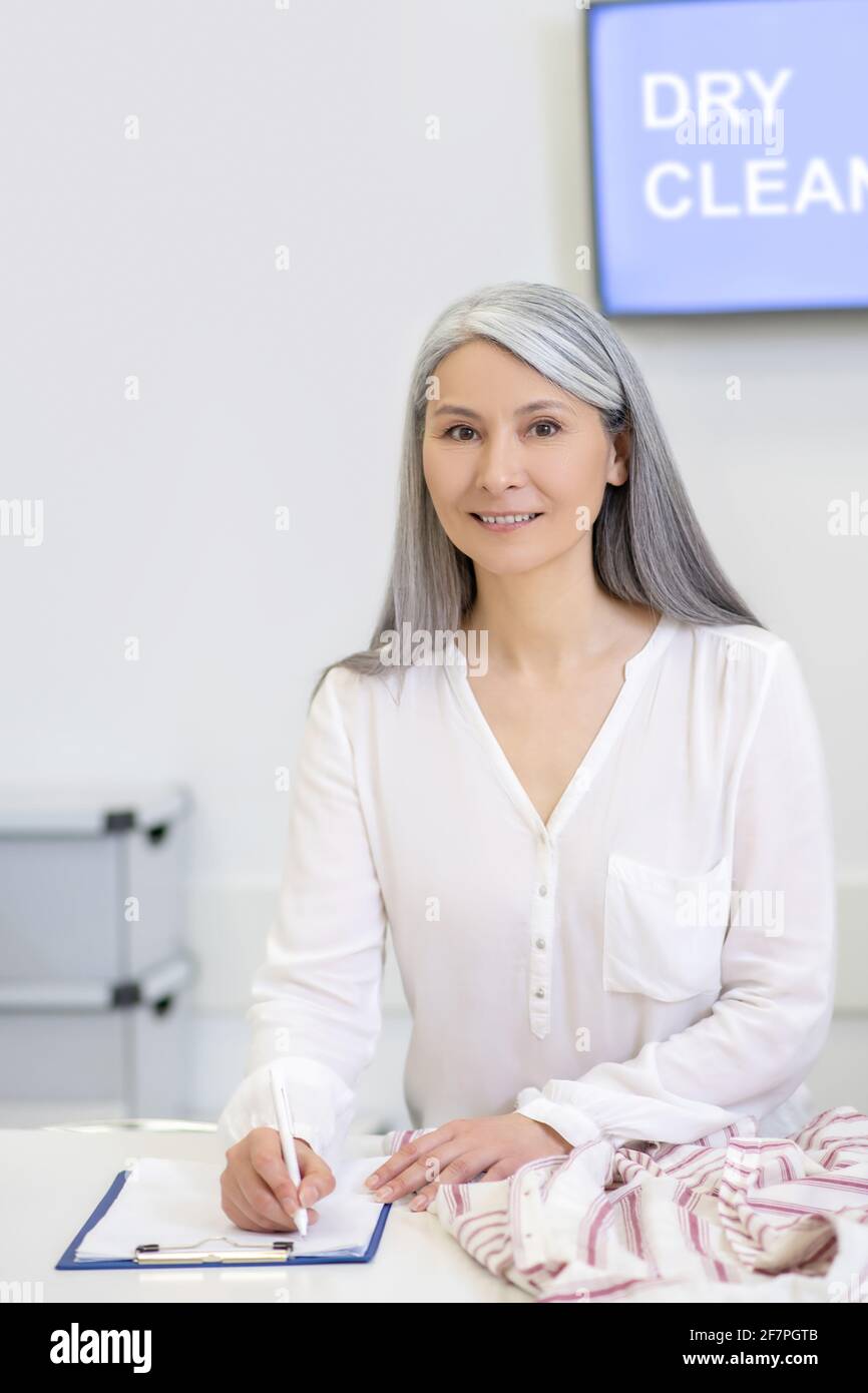 Woman standing behind counter writing document Stock Photo - Alamy