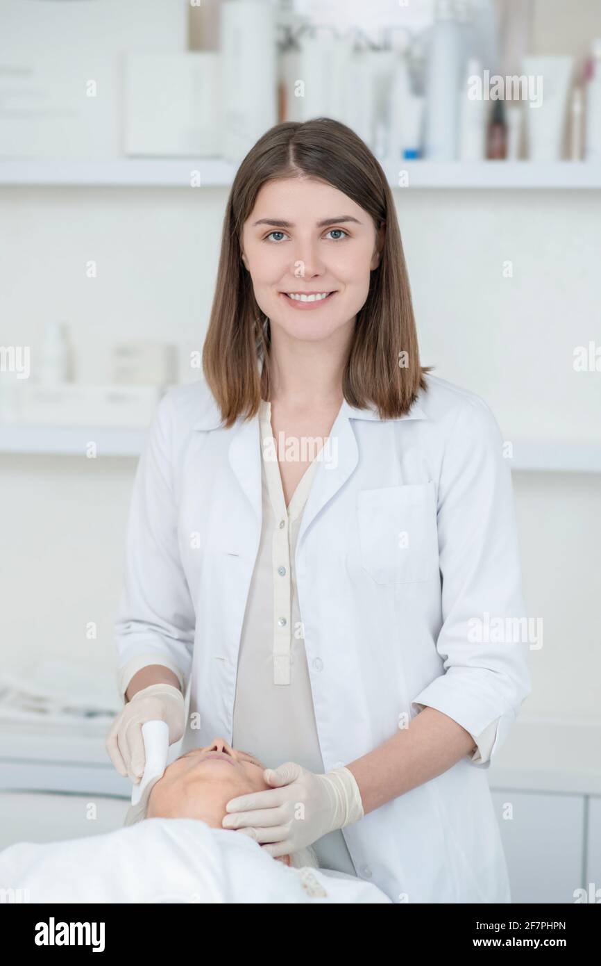 Young dark-haired cosmetologist at work looking positive Stock Photo ...