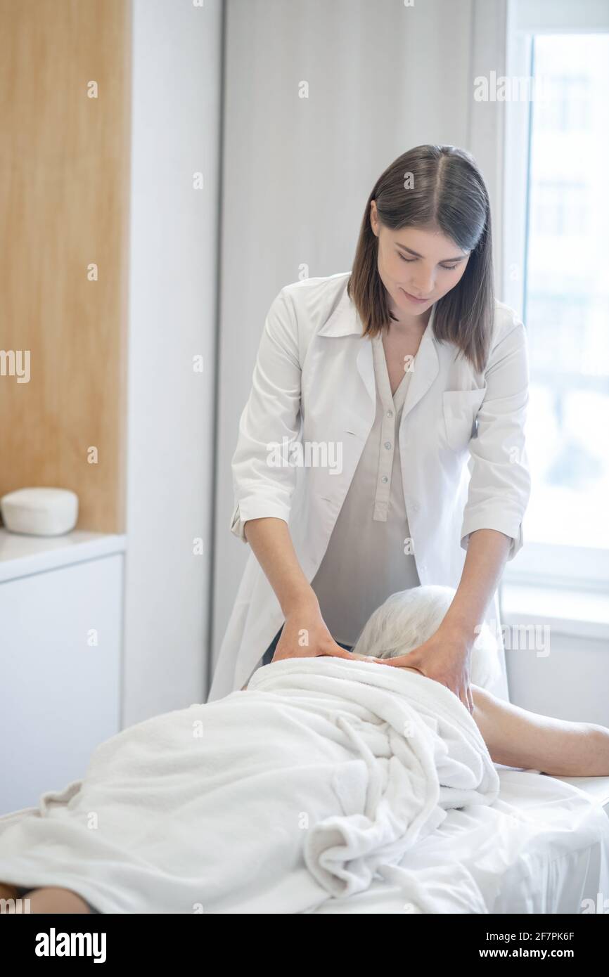 Female massage therapist working with a female senior patient Stock ...
