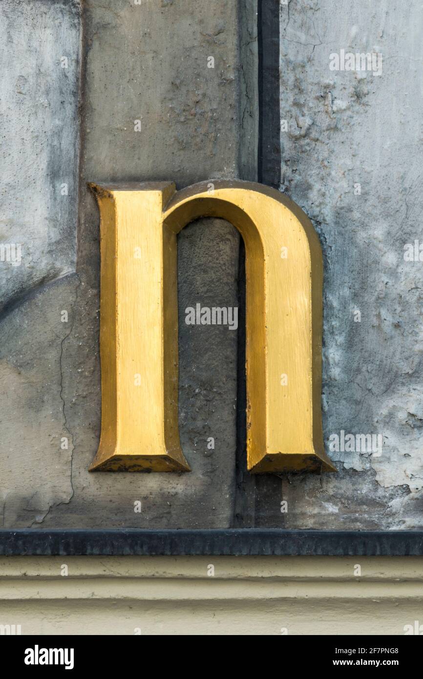 Historic golden letter n on a grey wall Stock Photo - Alamy