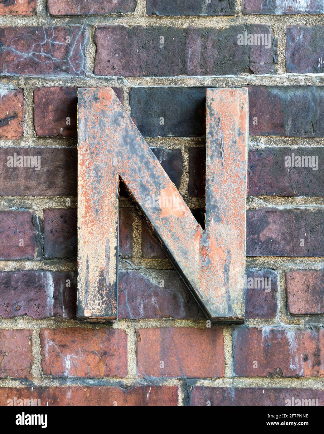 Weathered metal letter N in front of a brick wall Stock Photo - Alamy