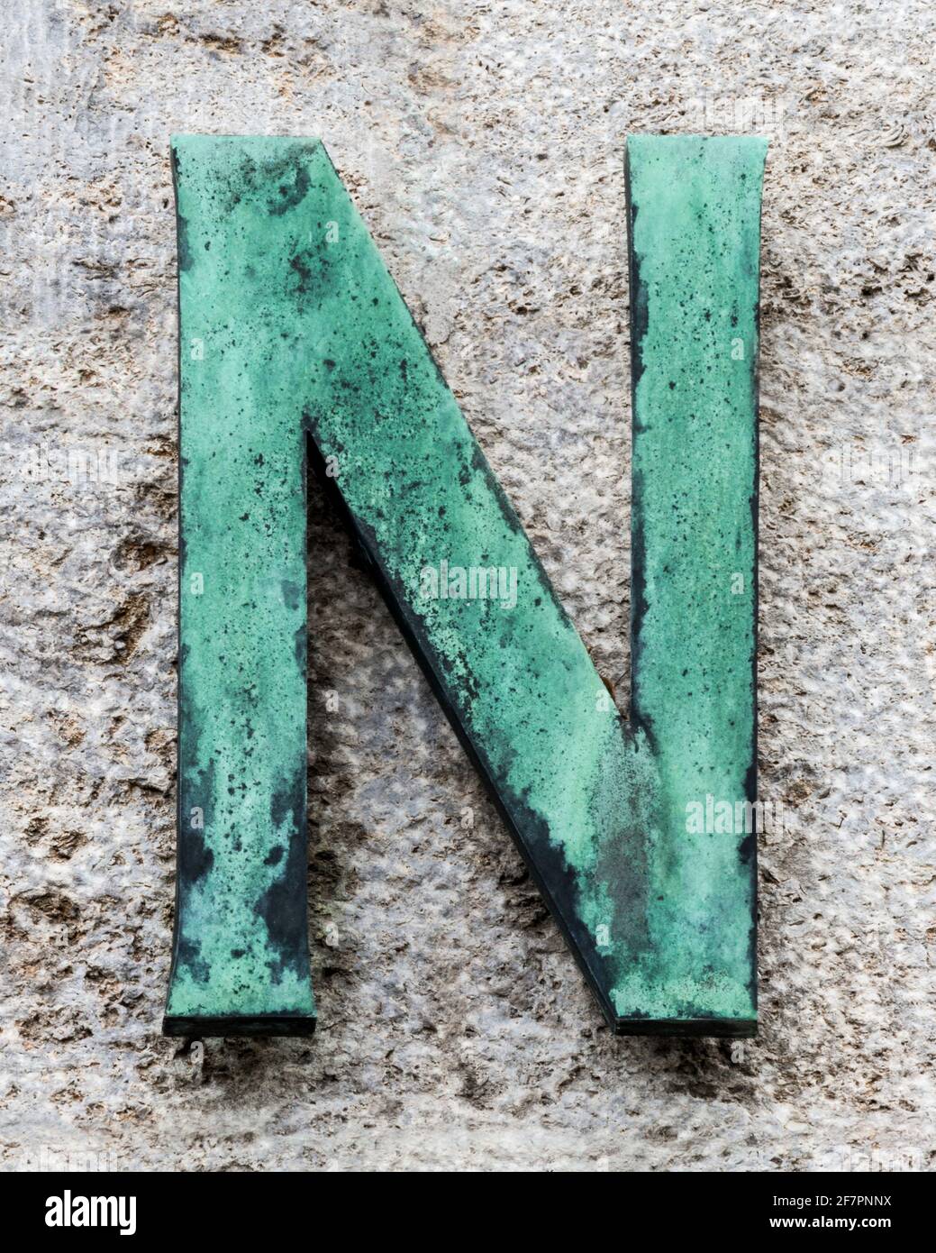 Metal letter N covered with verdigris on a natural stone wall Stock ...