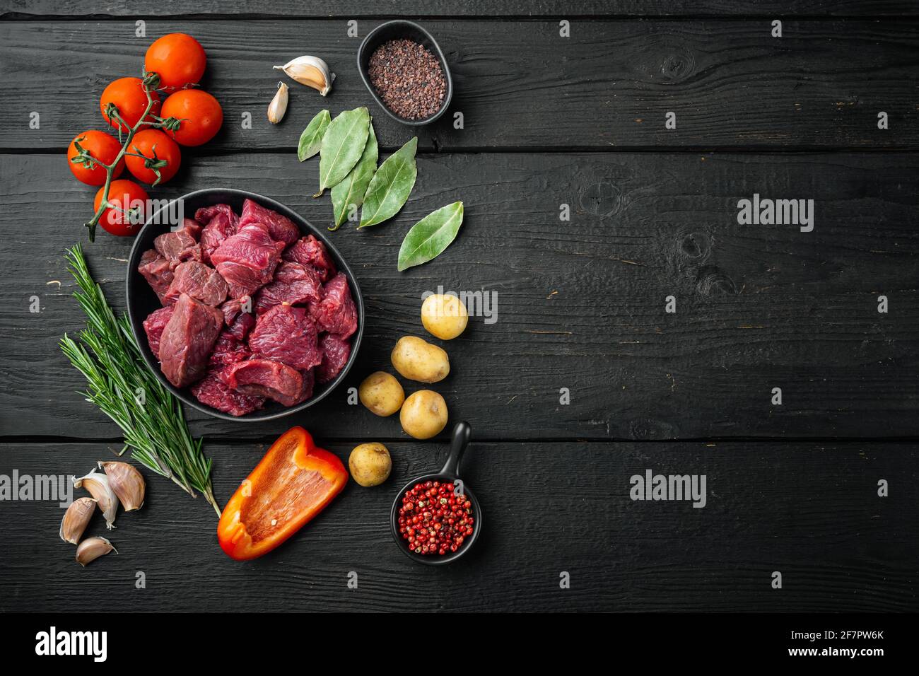 Raw lean stewing beef set and potatoe, on black wooden background, top ...