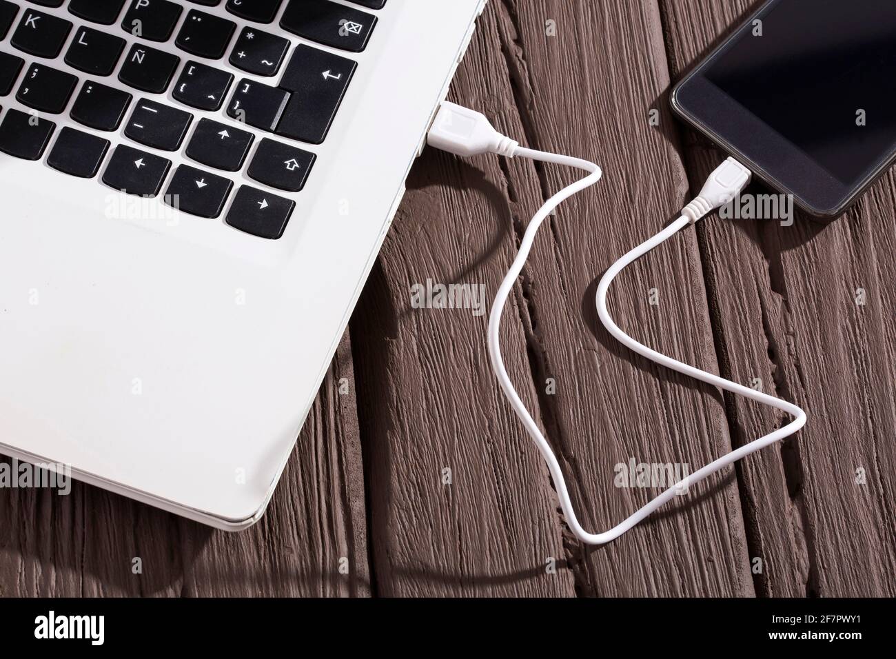Phone connected to the computer - Wooden background Stock Photo - Alamy