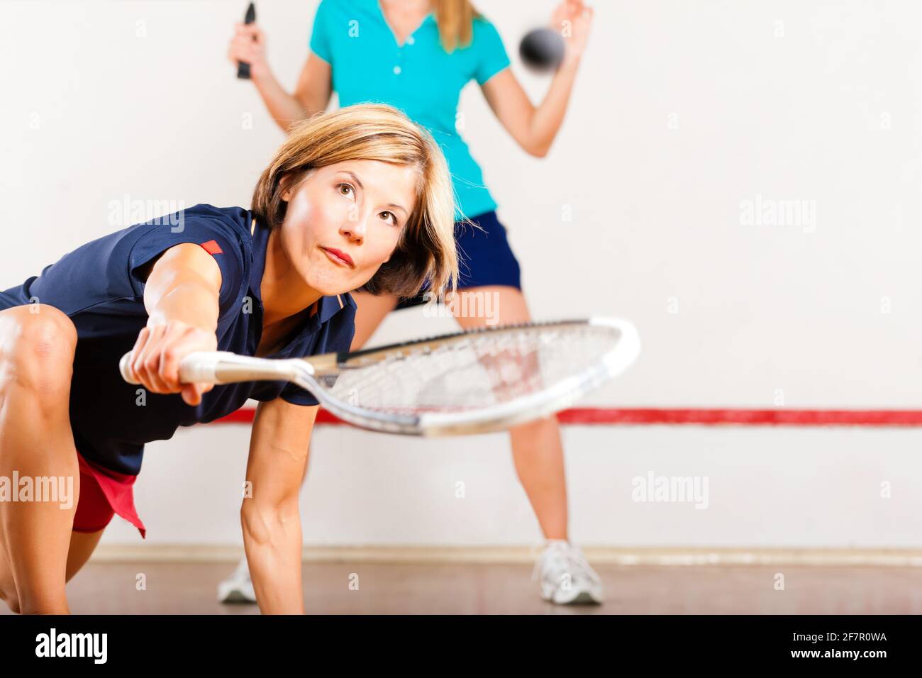Two women playing squash as racket sport in gym, it might be a ...