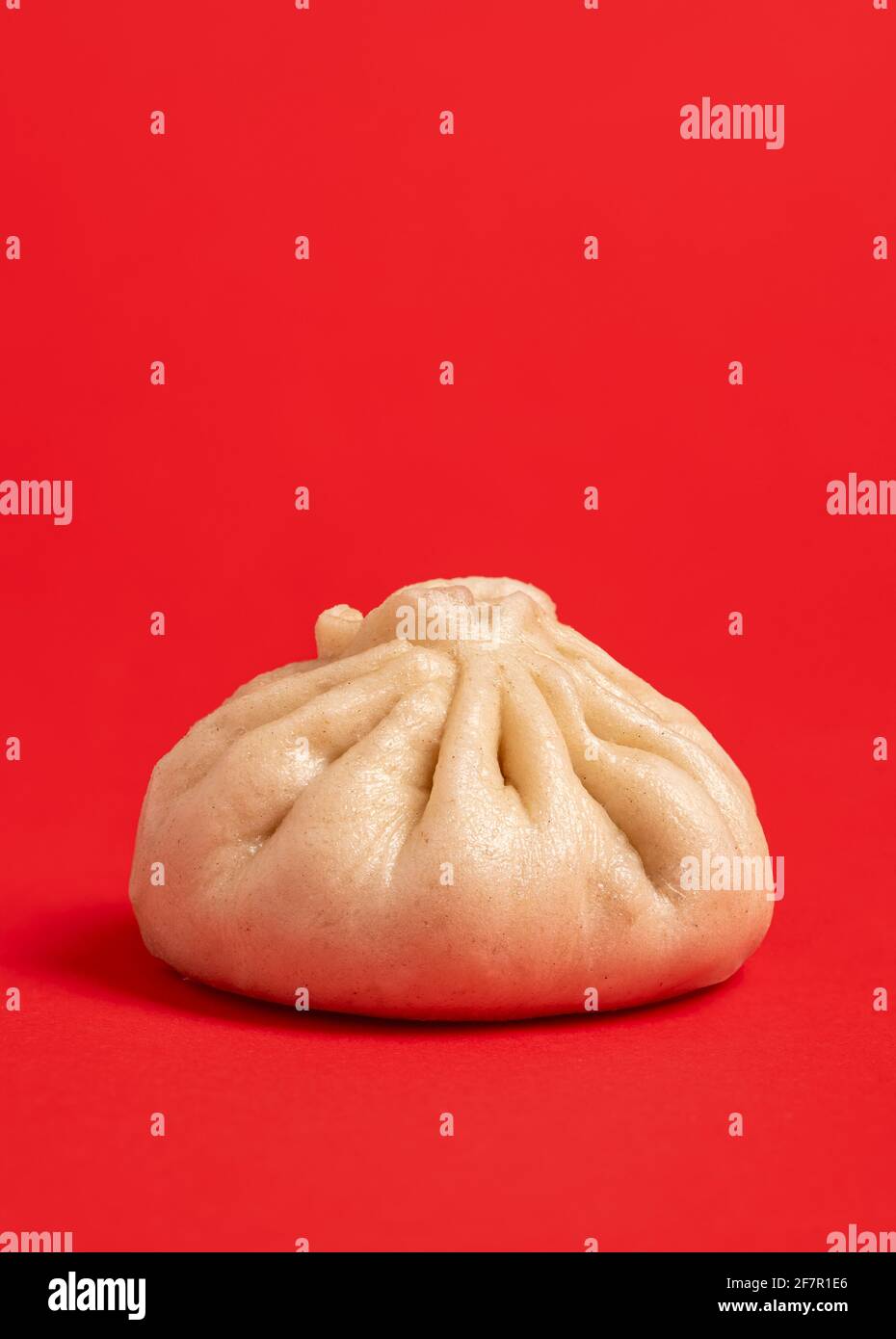 Close-up with a single bao dumpling isolated on a red colored ...