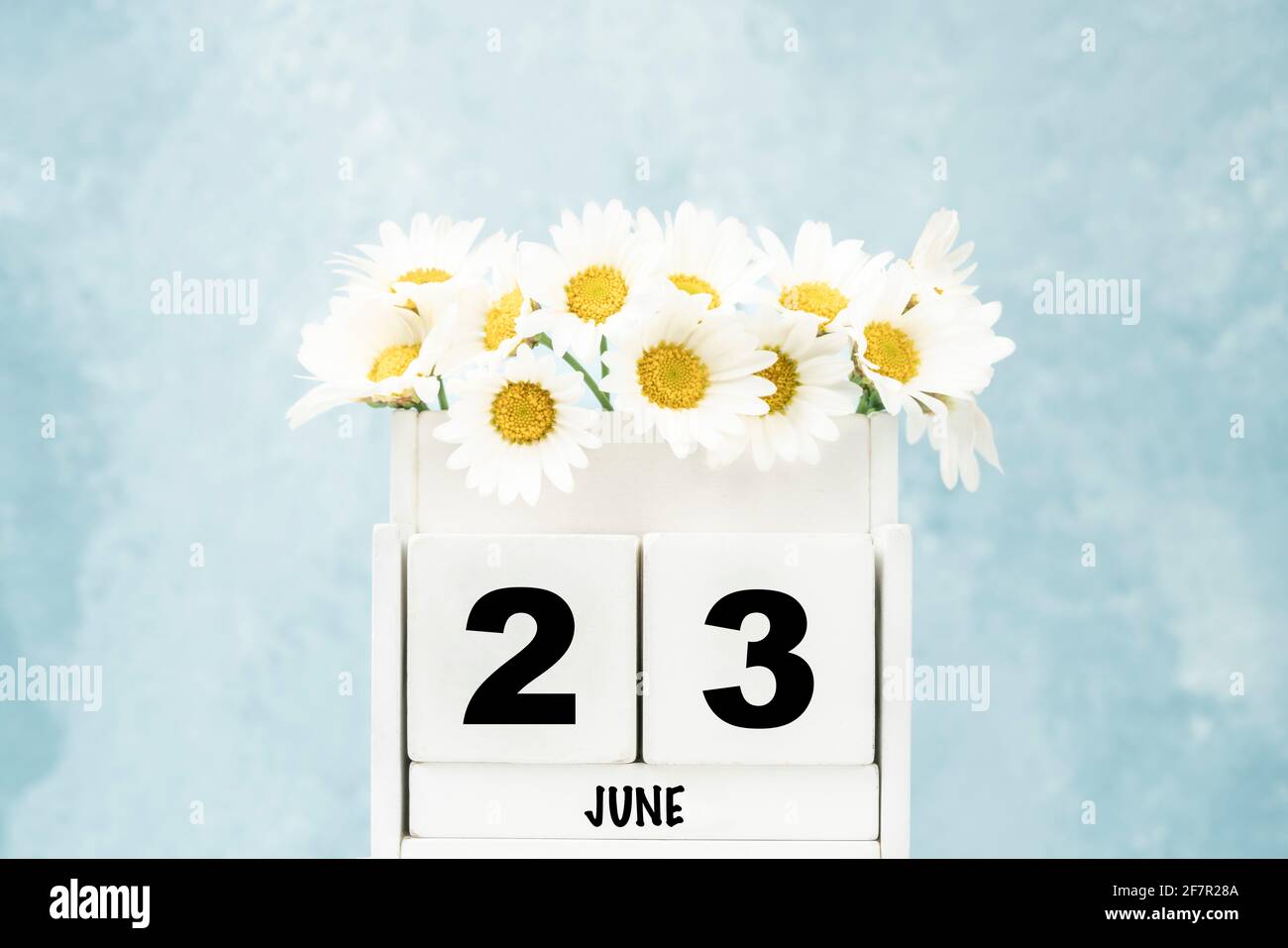 White cube calendar for June with daisy flowers over blue background ...