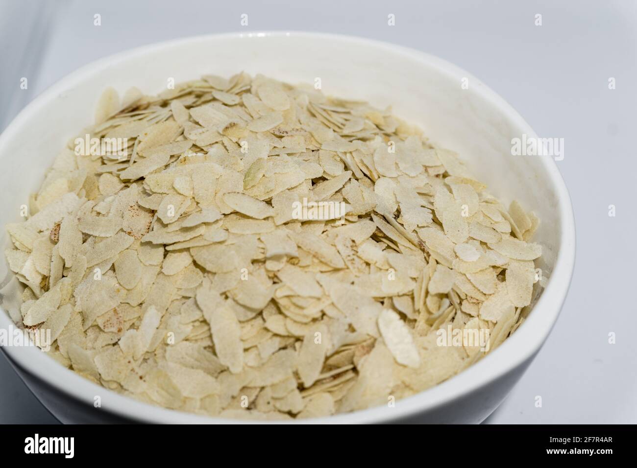 A closeup shot of a bowl of flattened rice.Flattened rice is rice which ...