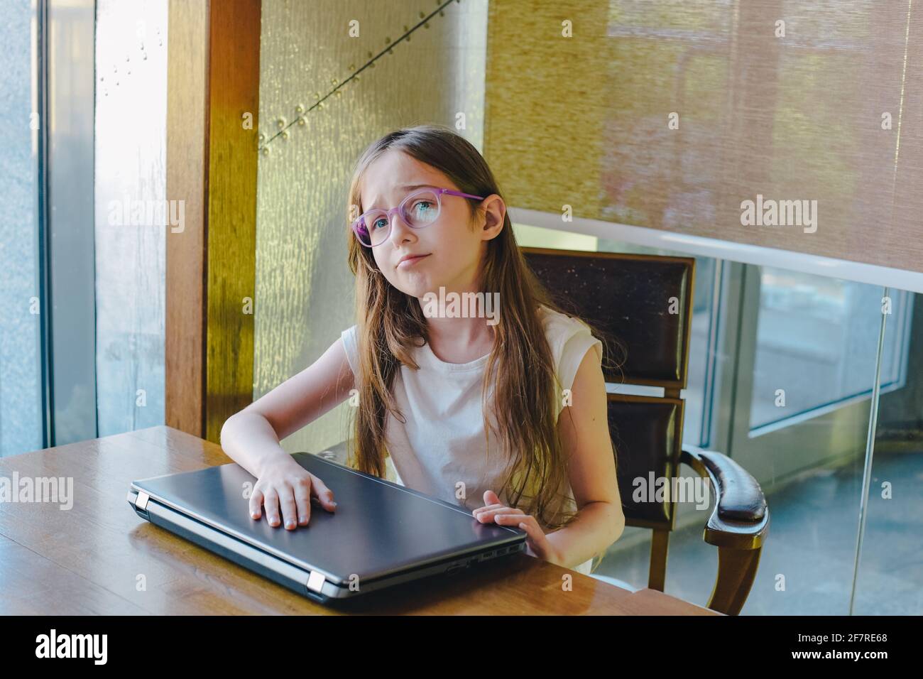 Portrait of sad little girl with laptop computer. Upset teenager girl ...