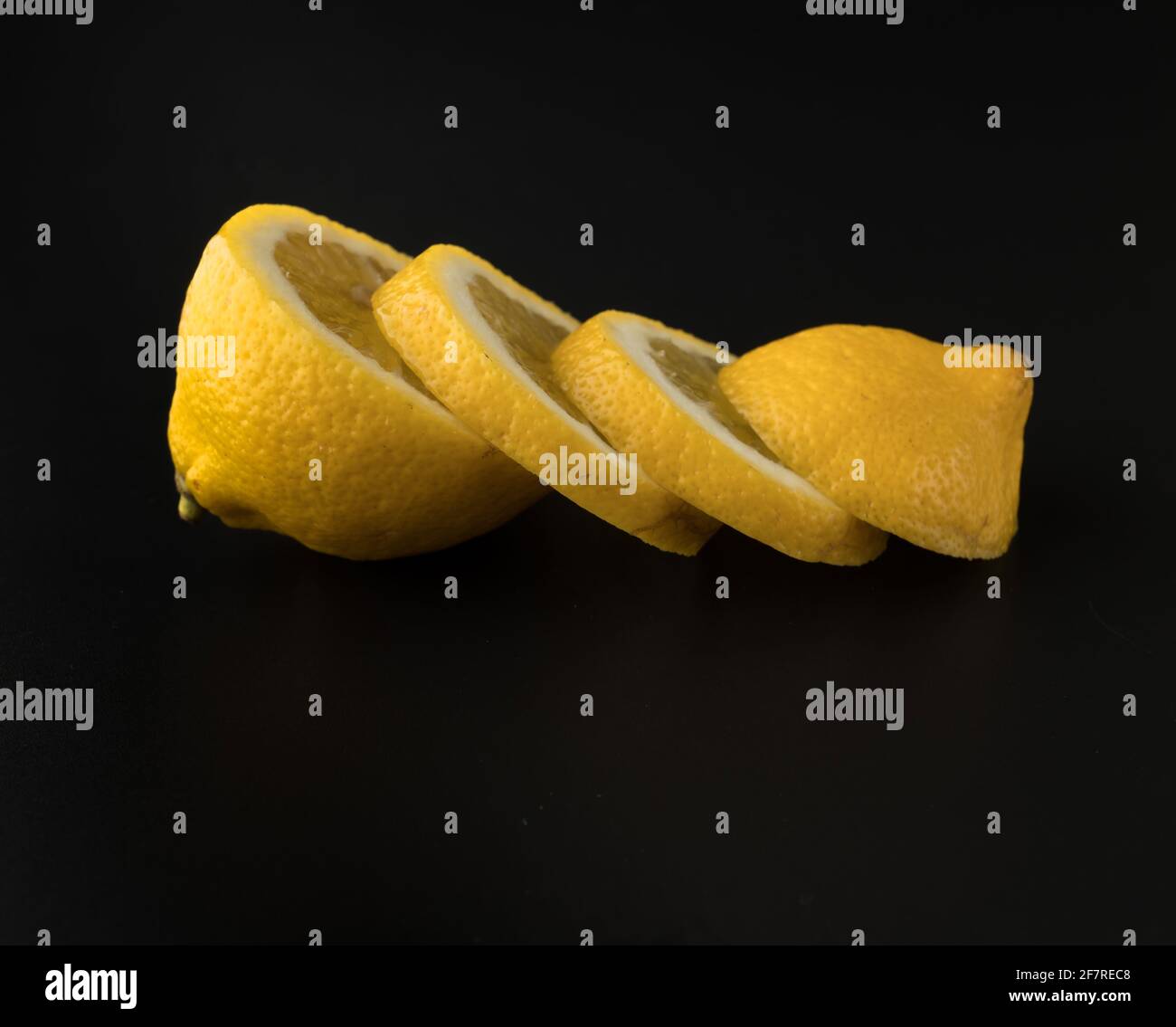 Lemon cut into round slices and slices arranged, in a row on black ...