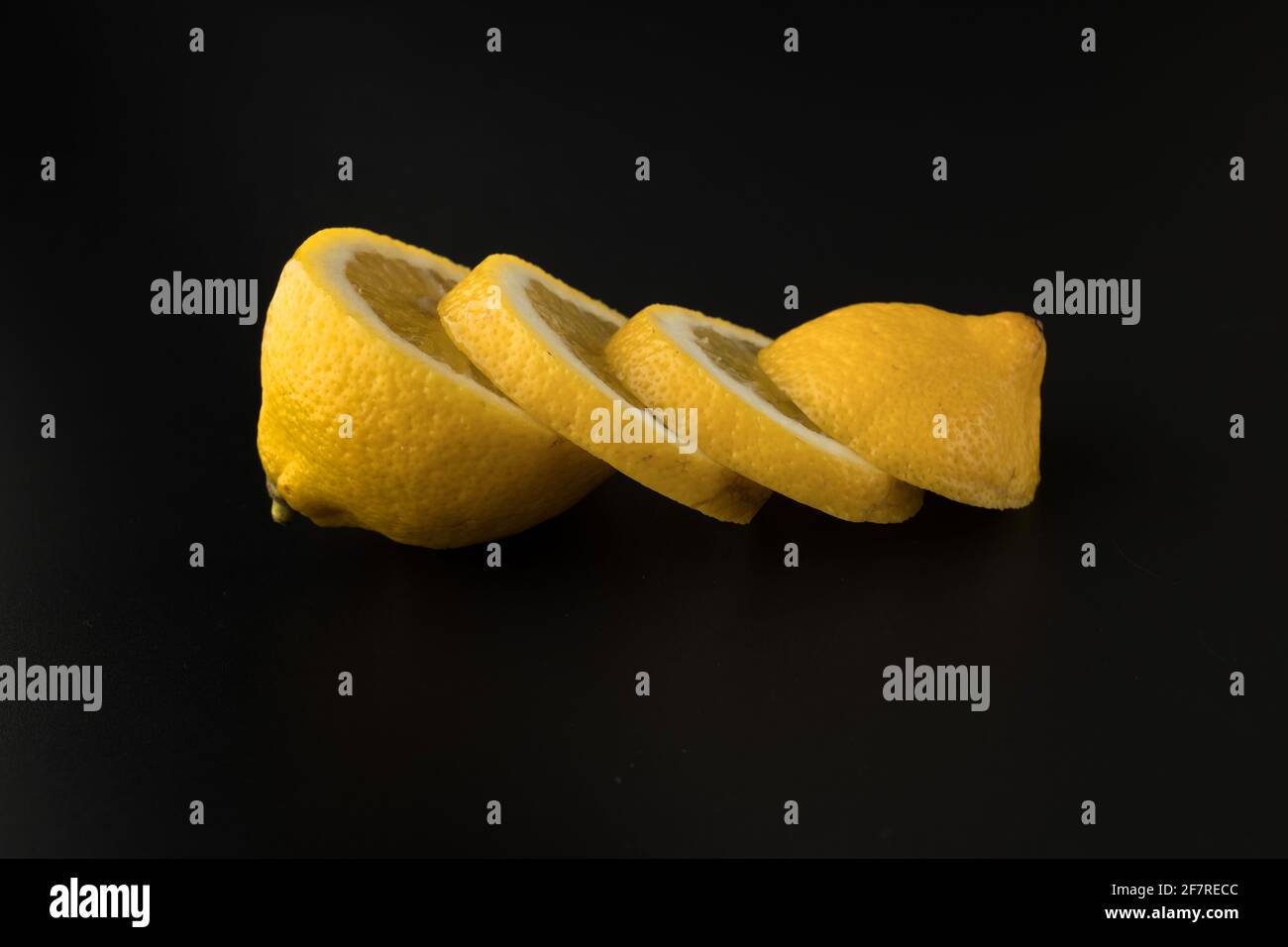 Lemon cut into round slices and slices arranged, in a row on black ...
