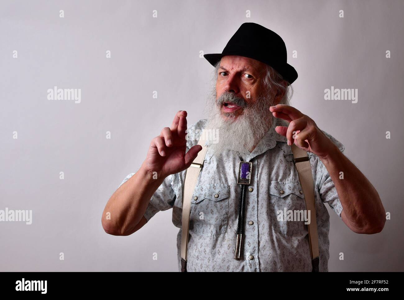 Senior Caucasian bearded male trying to ward off bad luck with fingers ...