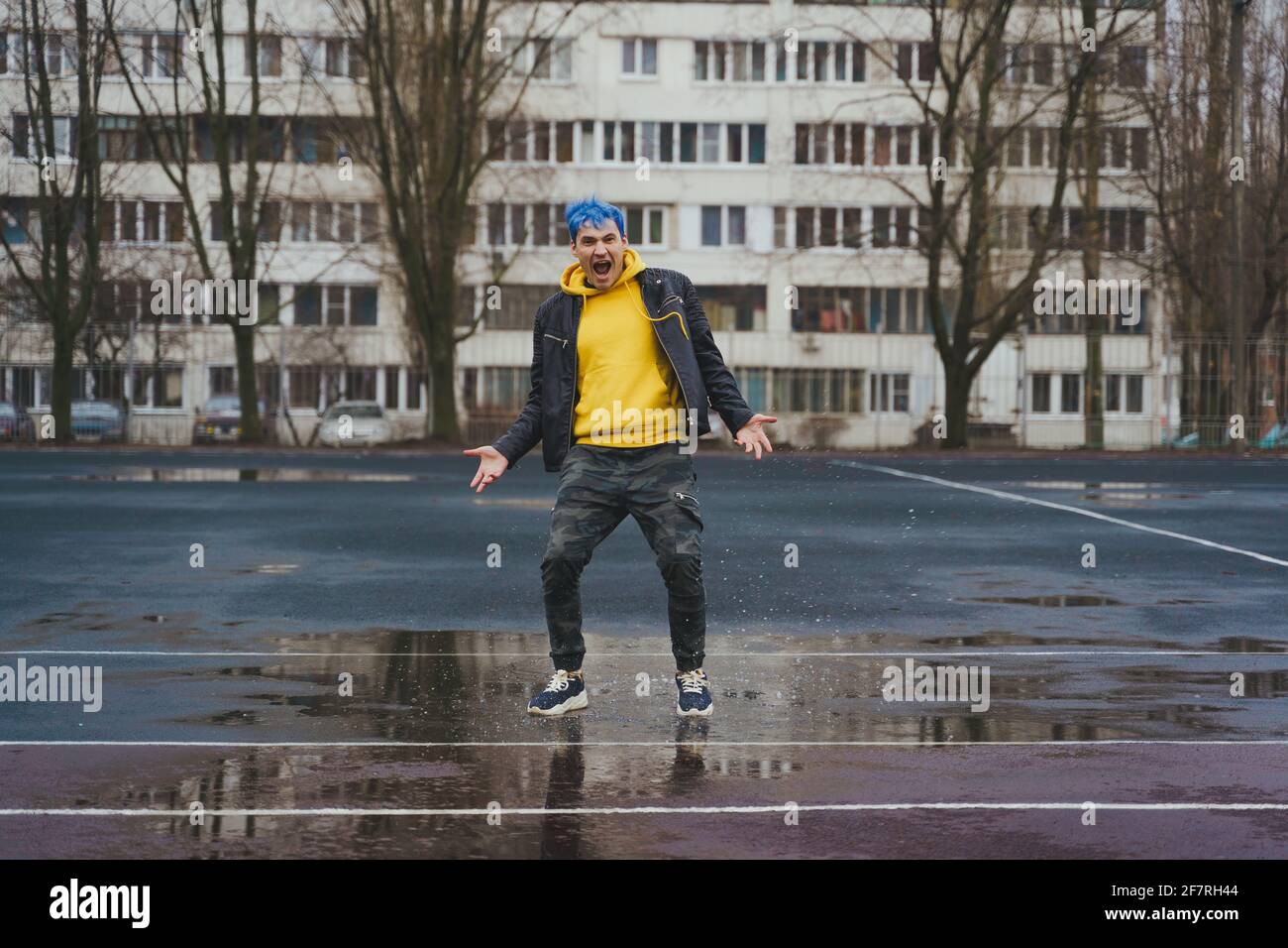 Young man standing in puddle on sports stadium on background of high ...