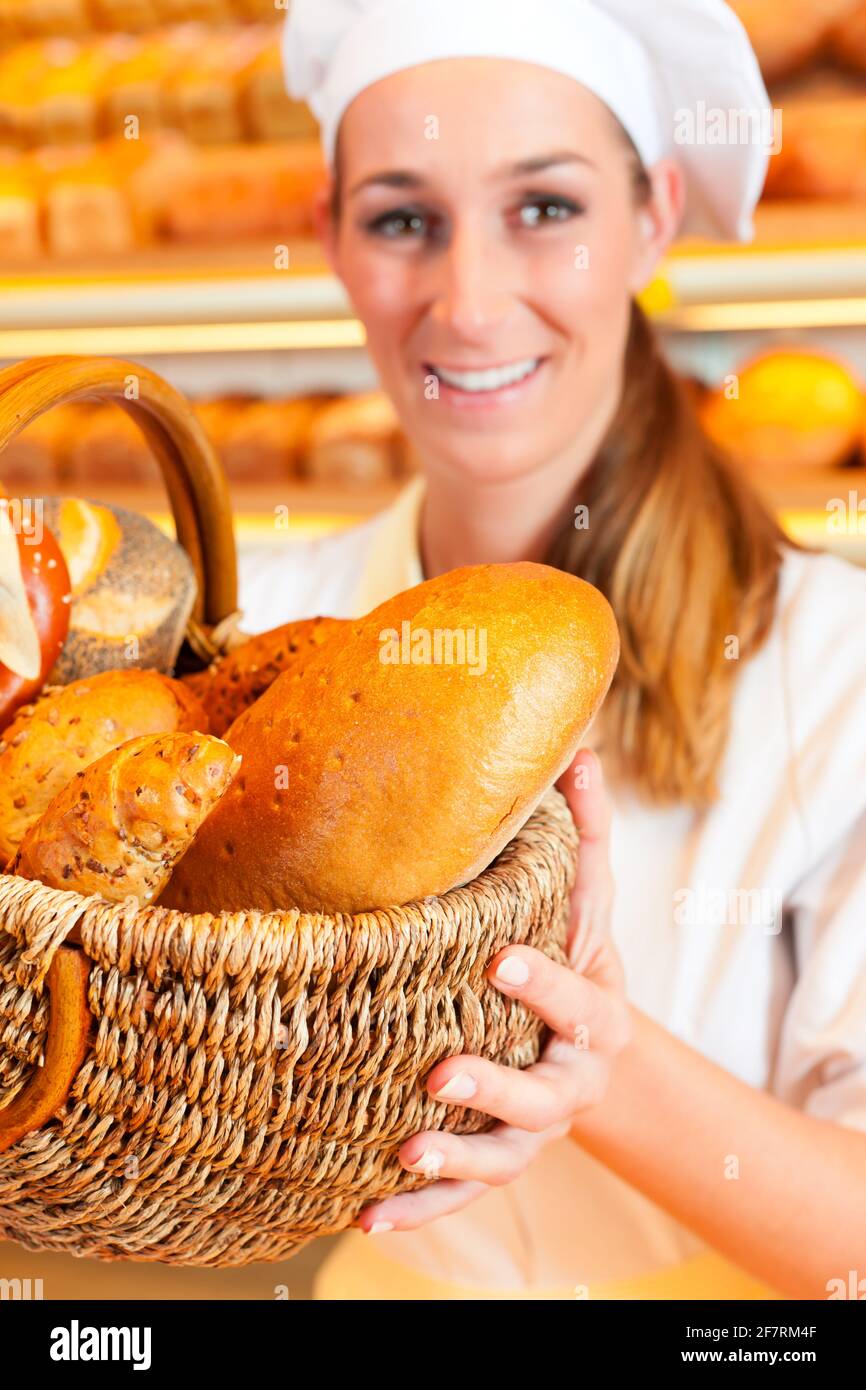 Female baker or saleswoman in her bakery selling fresh bread, pastries ...