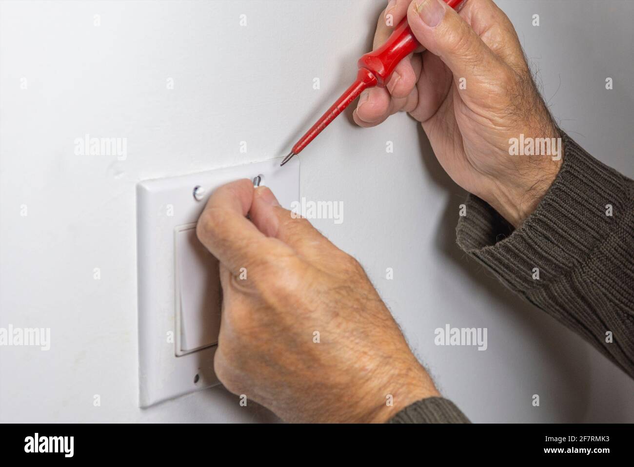 The electrician prepared the screws for securing the switch cover and ...