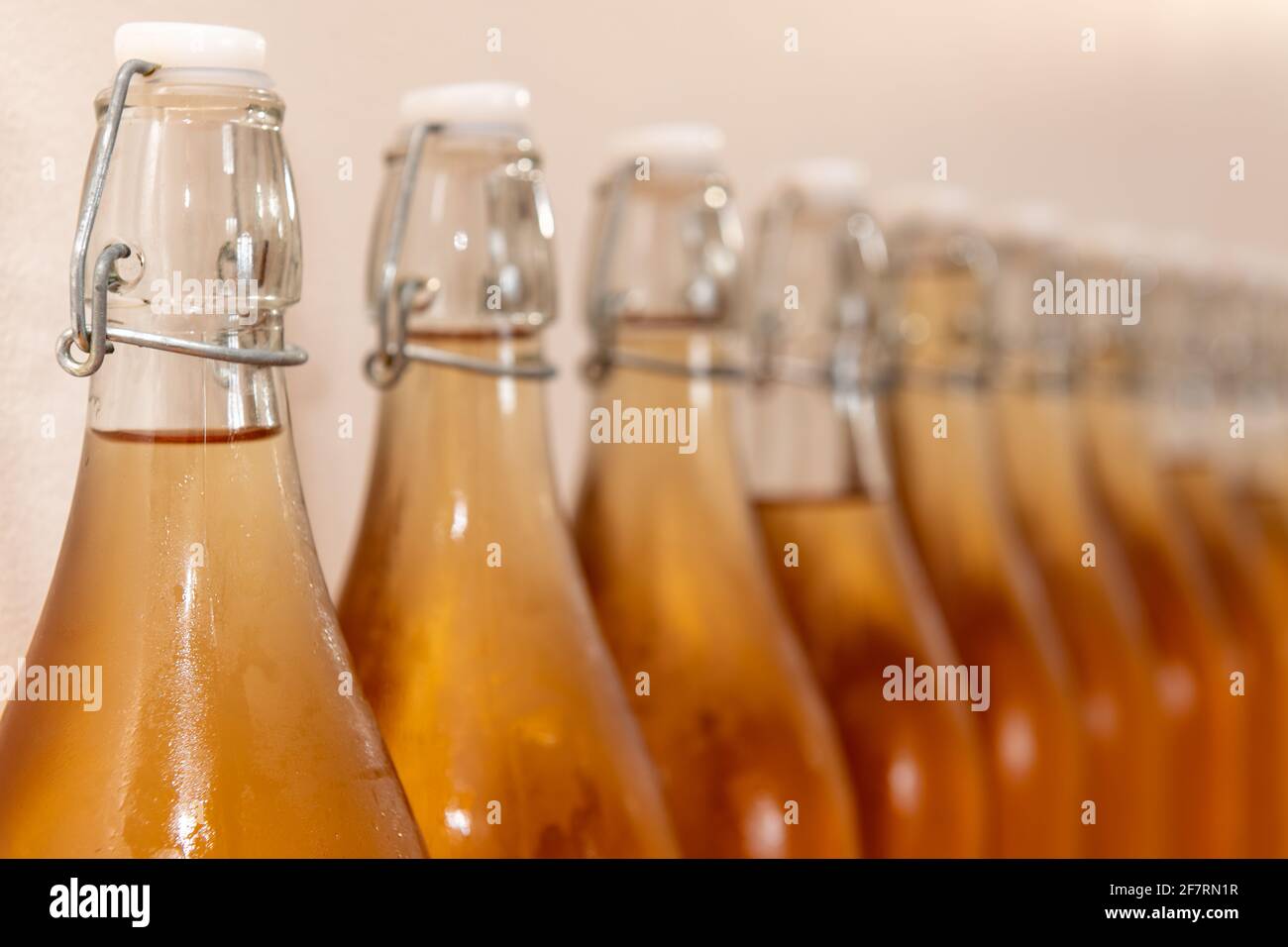 Close up of a row of flip top bottles of home made cider covered in ...