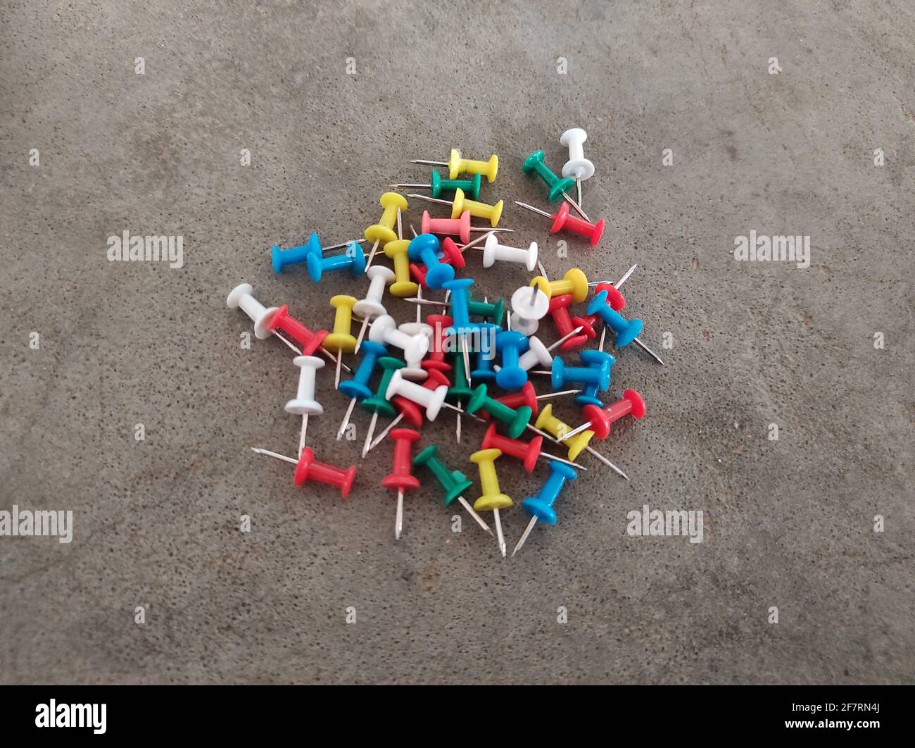 Top view of a pile of colorful push pins on a concrete floor ground ...