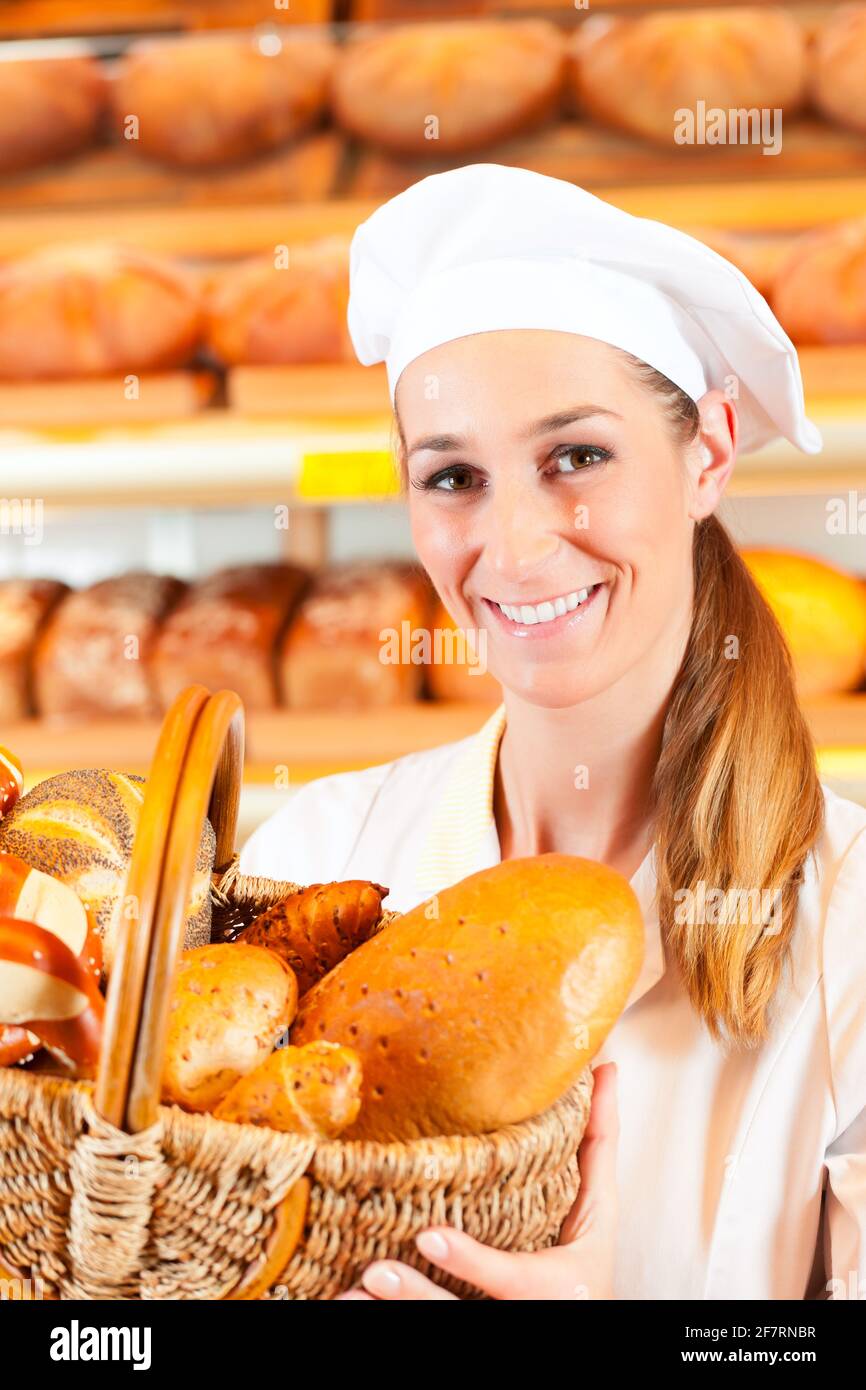 Female baker or saleswoman in her bakery selling fresh bread, pastries ...