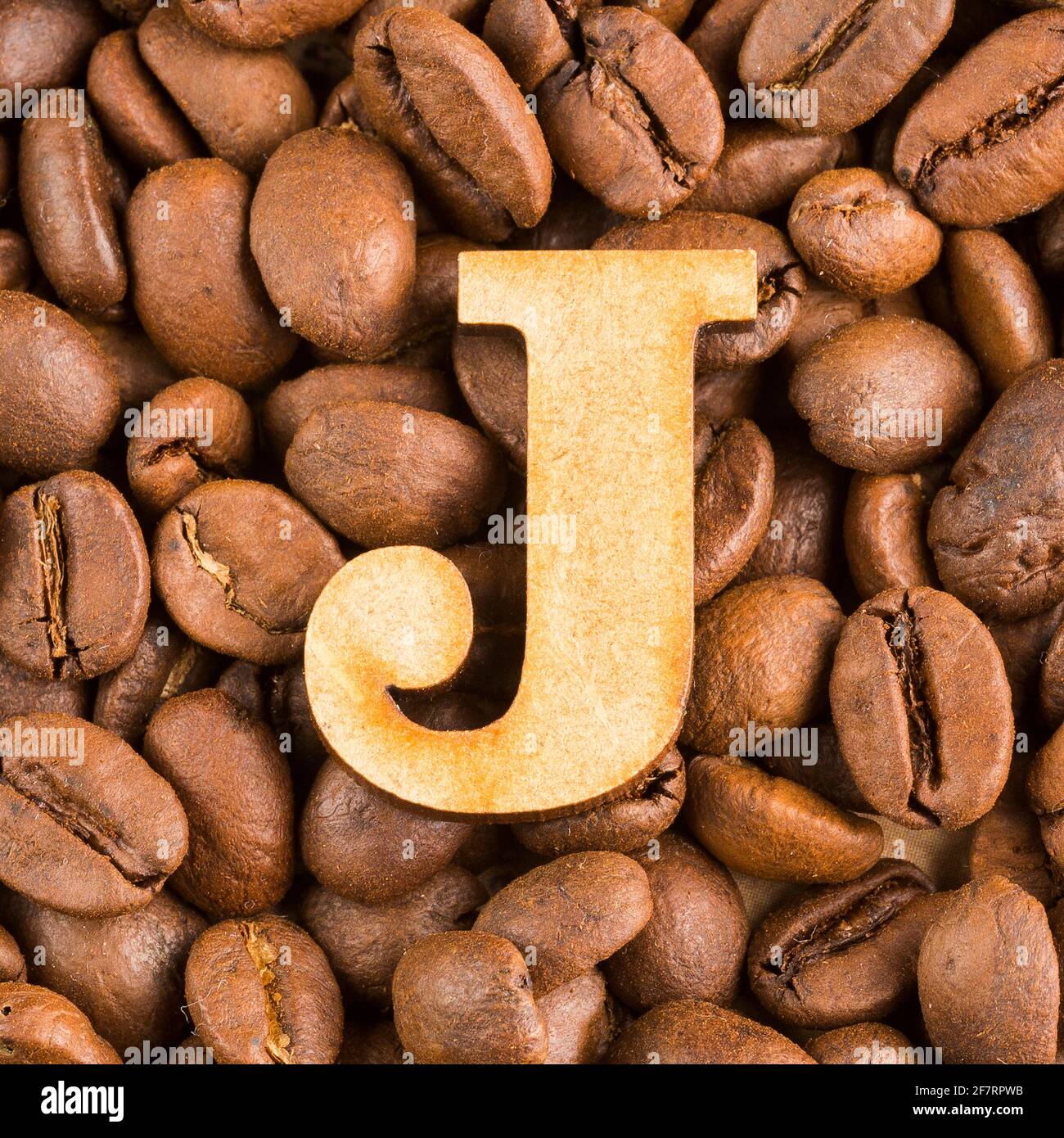 J, Letter of the alphabet on wood- background of coffee beans. Coffea ...