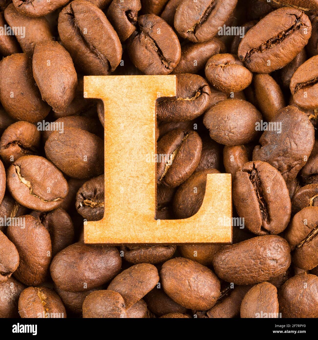 L, Letter of the alphabet on wood- background of coffee beans. Coffea ...