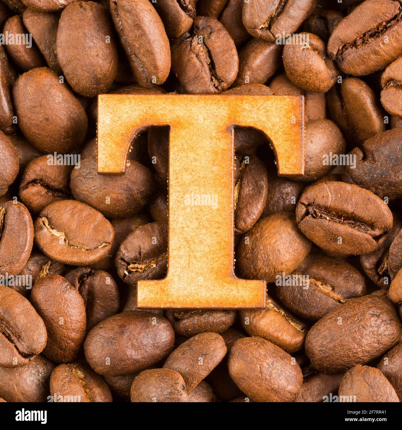 T, Letter of the alphabet on wood- background of coffee beans. Coffea ...