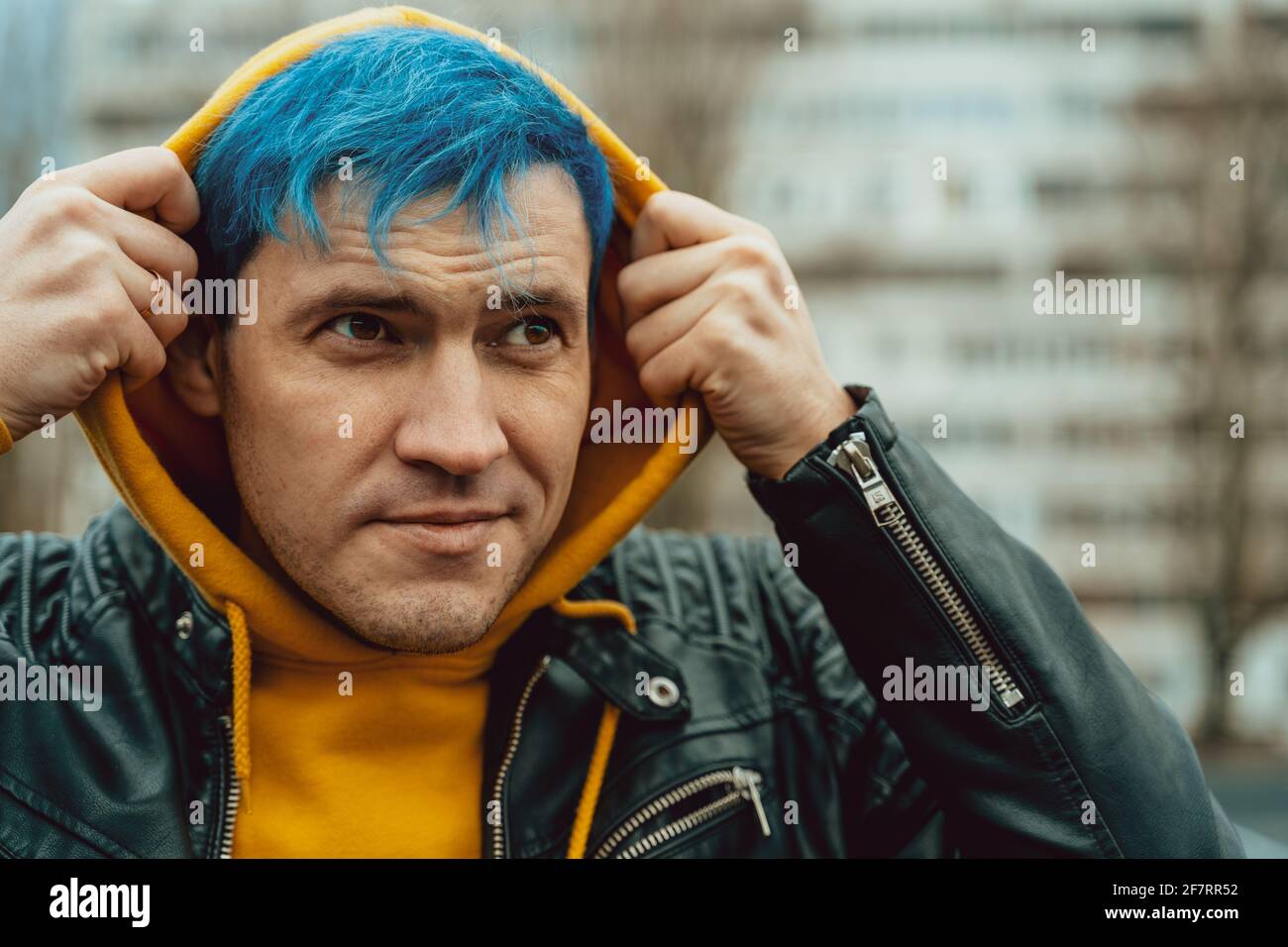 Portrait of young man in hood on background of high-rise building ...