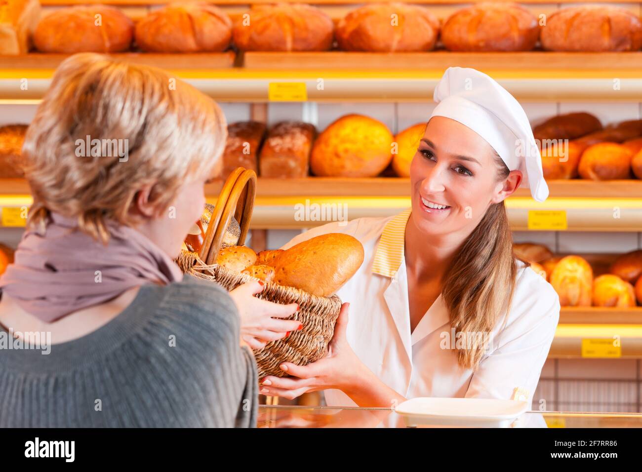 Female baker or saleswoman in her bakery with a female customer and ...