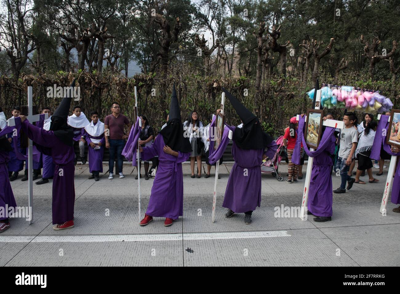 Hooded penitents carry crosses during Semana Santa procession in ...
