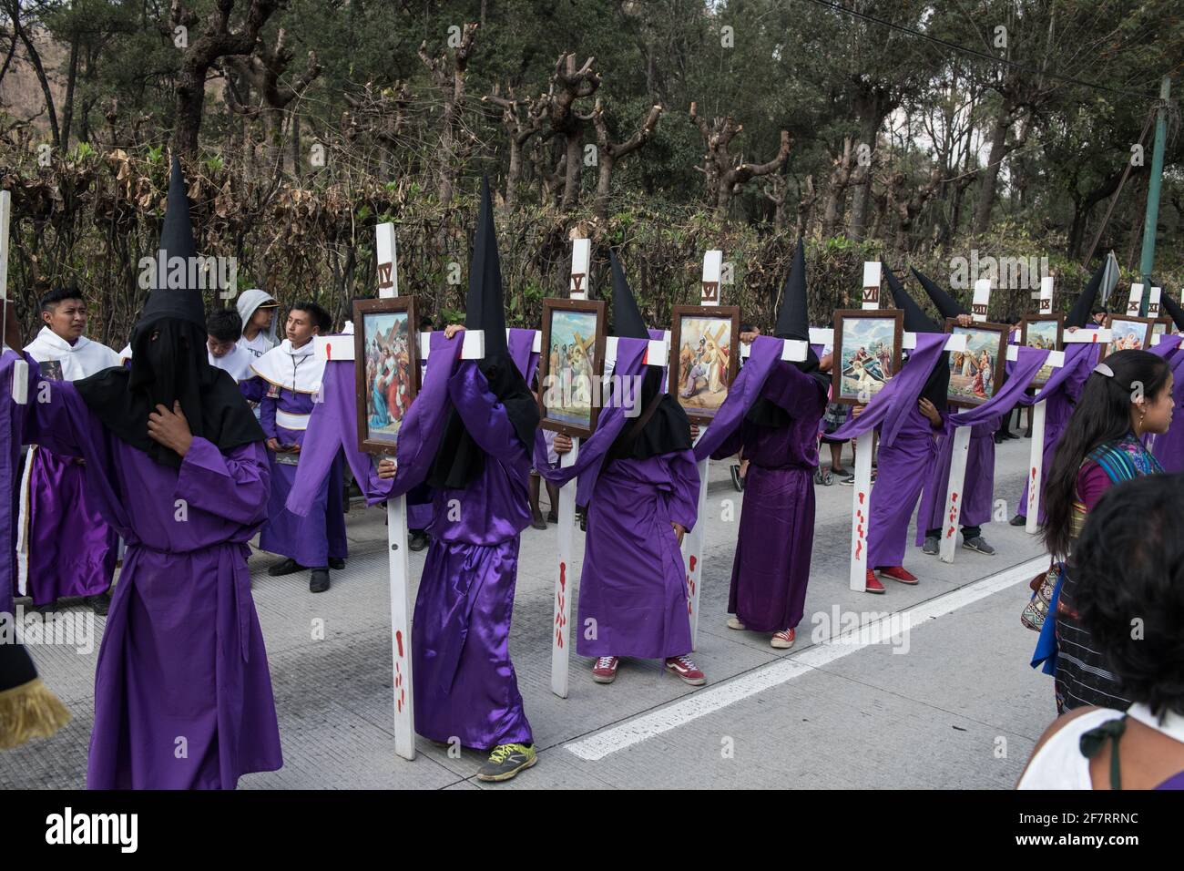 Hooded penitents carry crosses during Semana Santa procession in ...