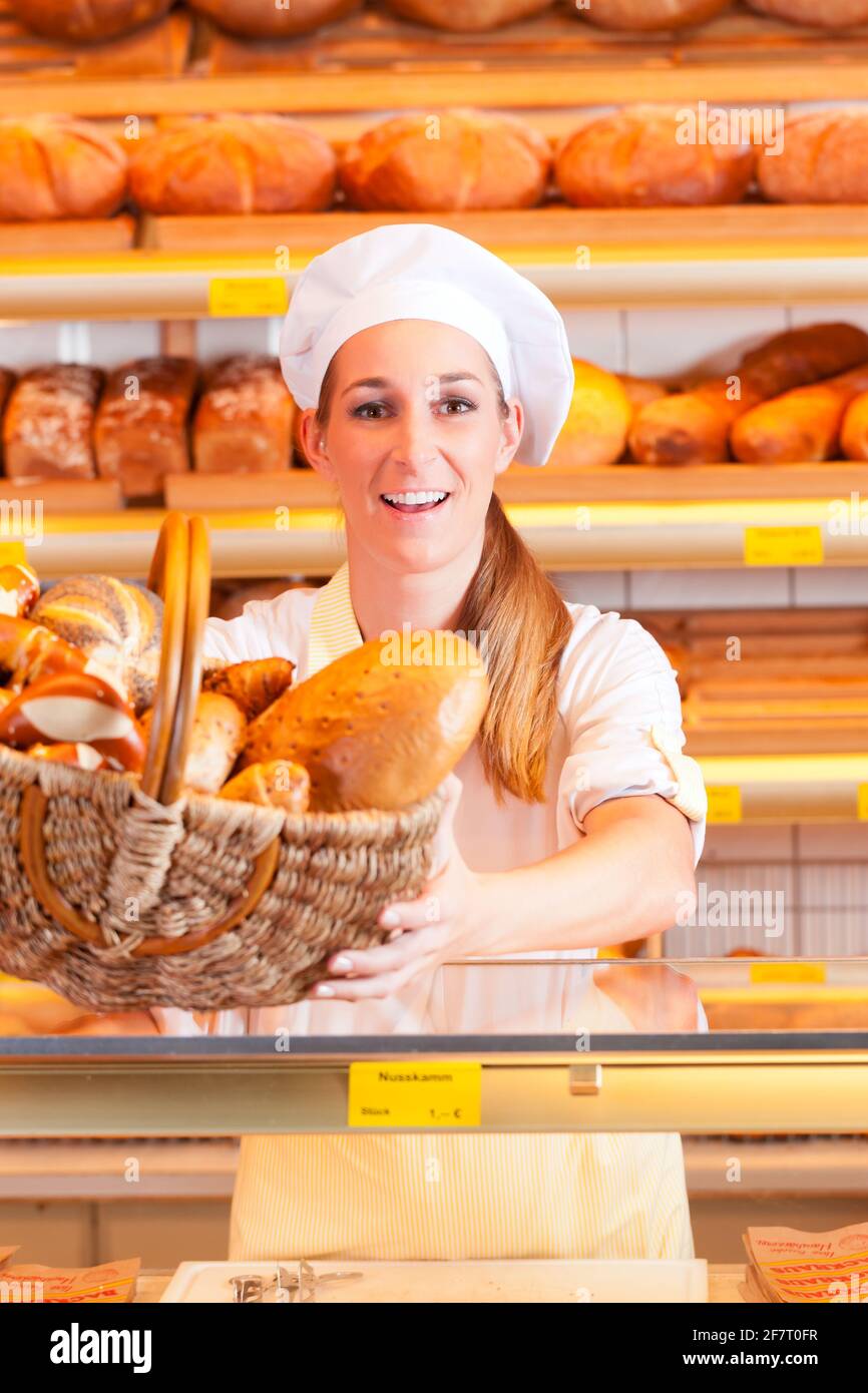 Female baker or saleswoman in her bakery with fresh pastries and bakery ...
