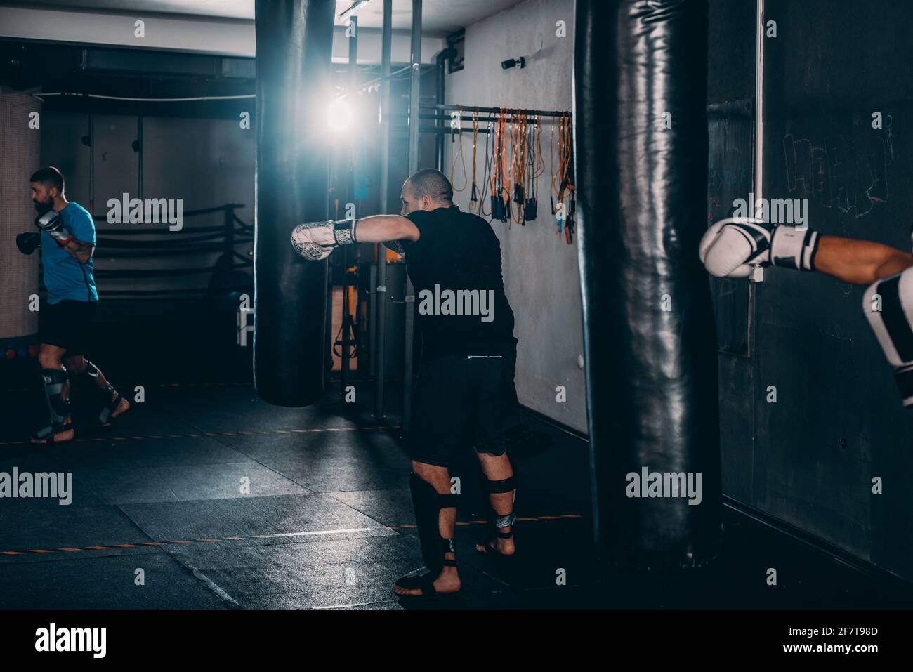 Silhouette male boxer hitting a huge punching bag at a boxing studio ...