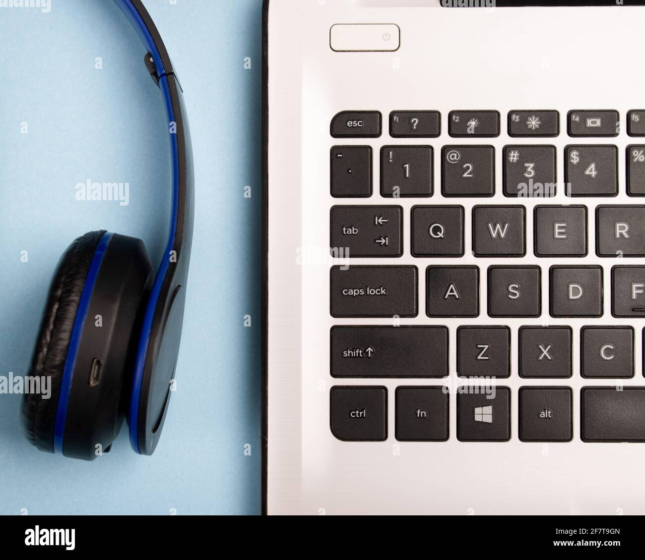 Headset next to an open laptop on a blue background Stock Photo - Alamy