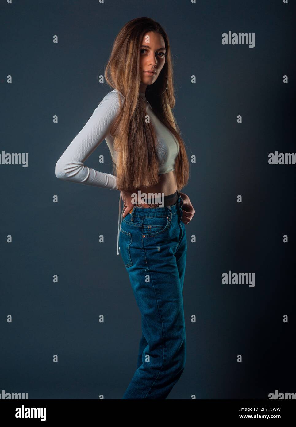 Stylish young woman wearing blue denim pants and white sweater Stock ...