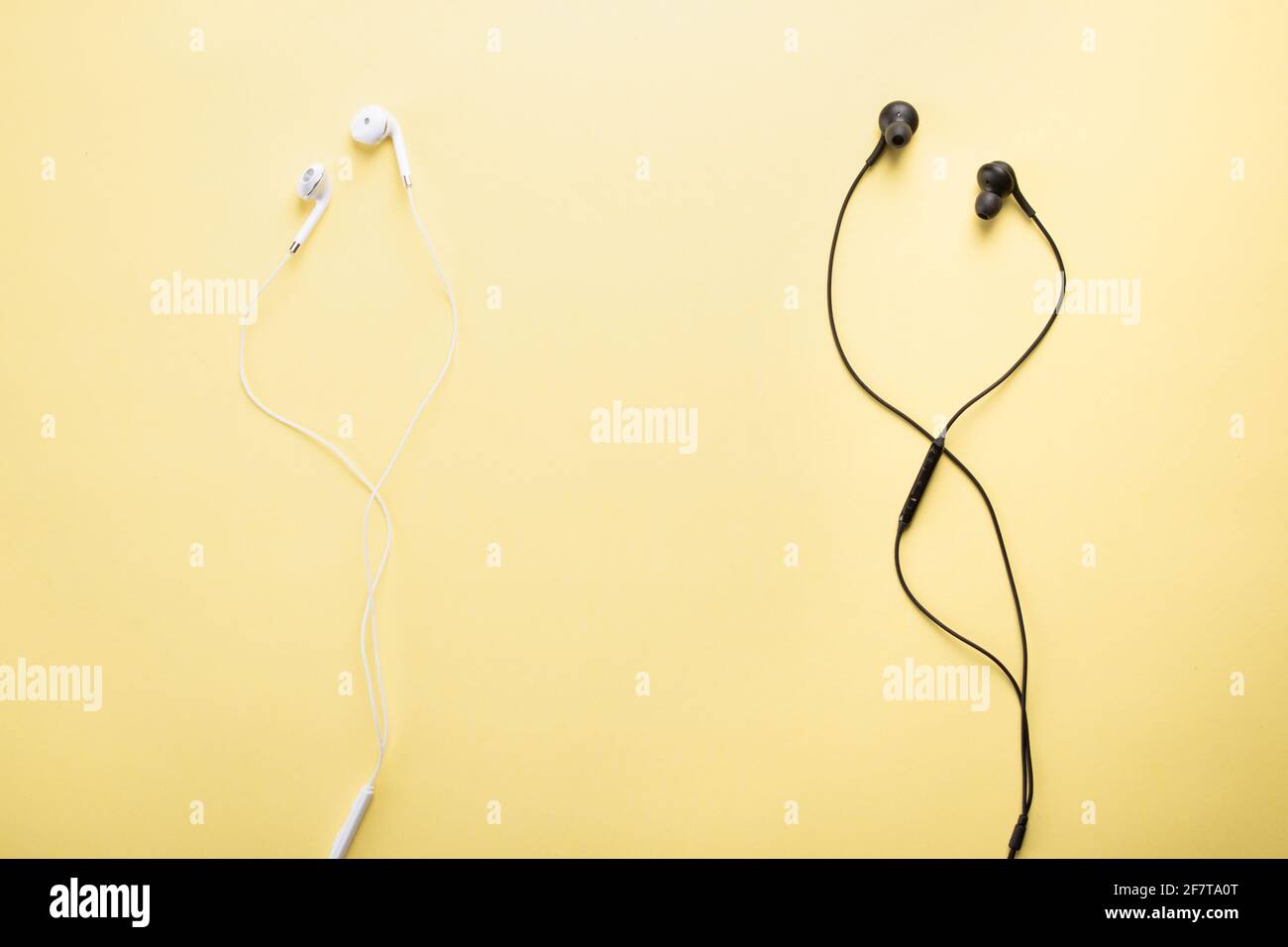 Top view of black and white earphones isolated on a yellow background ...