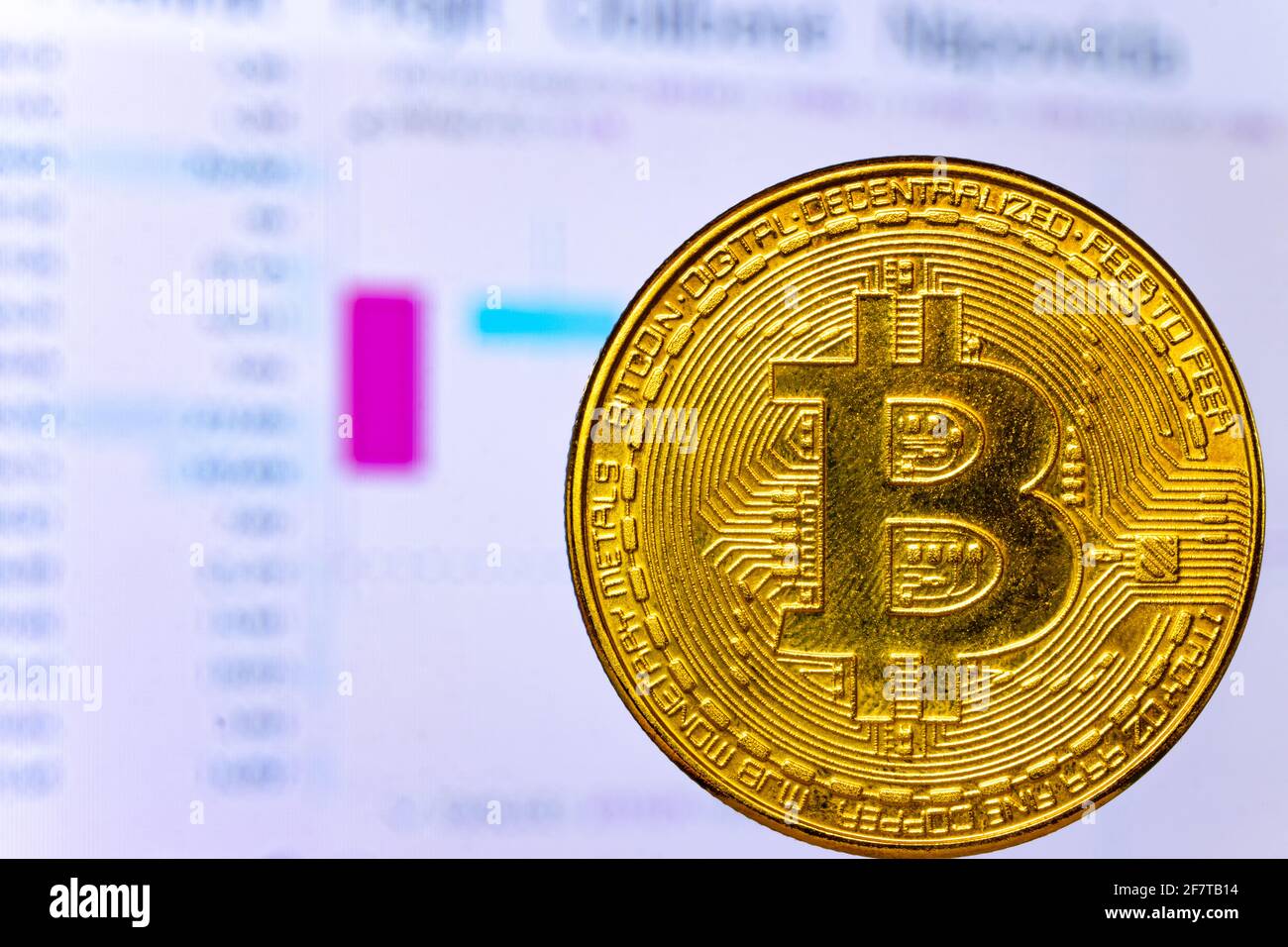 Bitcoin virtual currency in front of a screen with currency movement ...