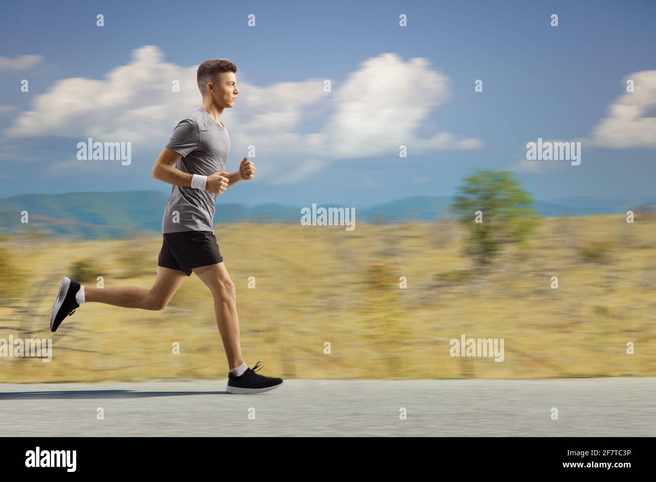 Full length shot of a young guy jogging in the countryside on an open ...