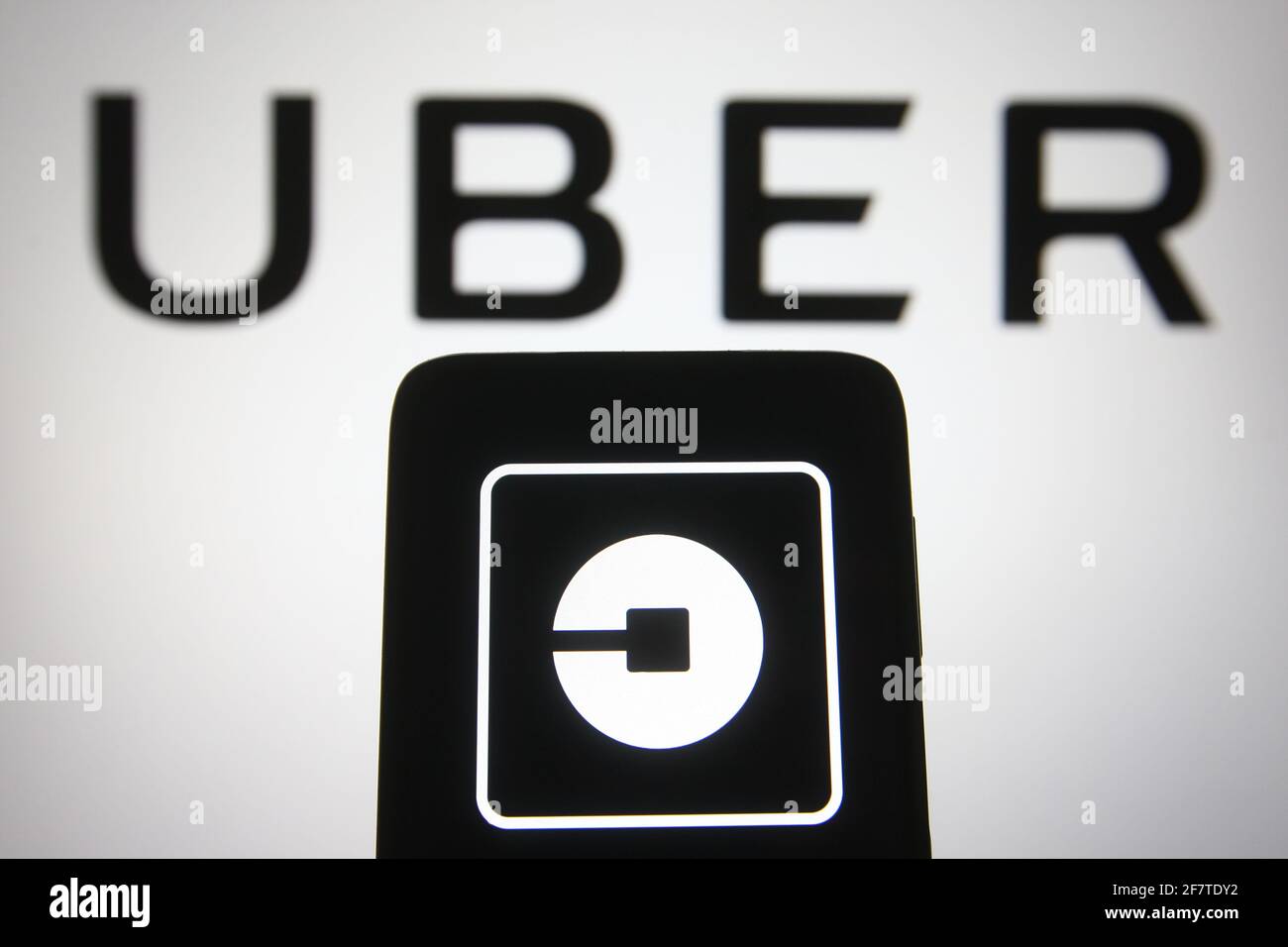 In this photo illustration an Uber logo is seen on a smartphone and a ...