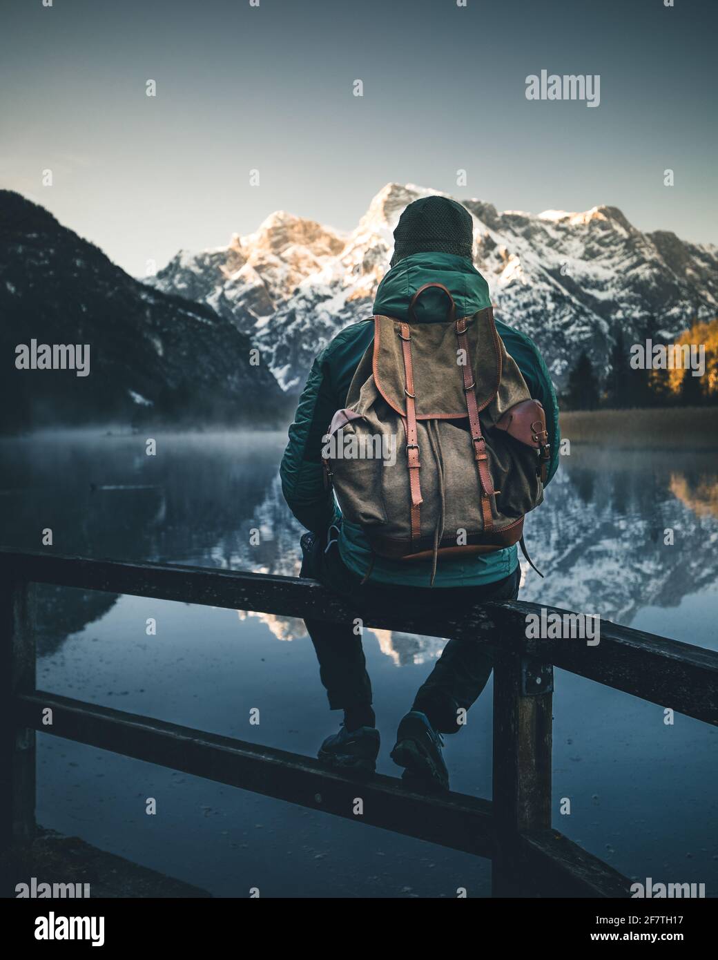 hiker with backpack in front of mountain lake with perfect reflection ...