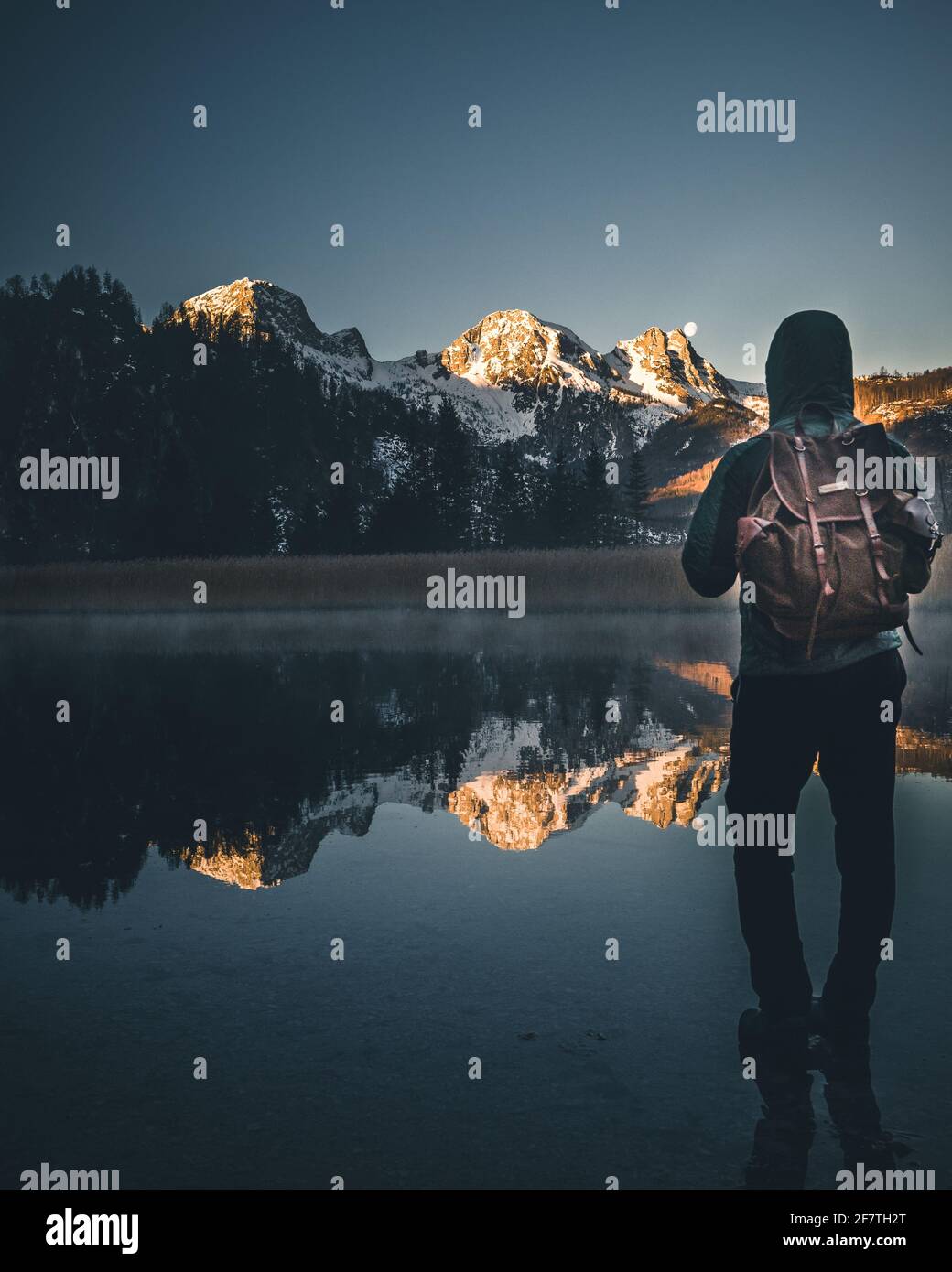 hiker with backpack in front of mountain lake with perfect reflection ...