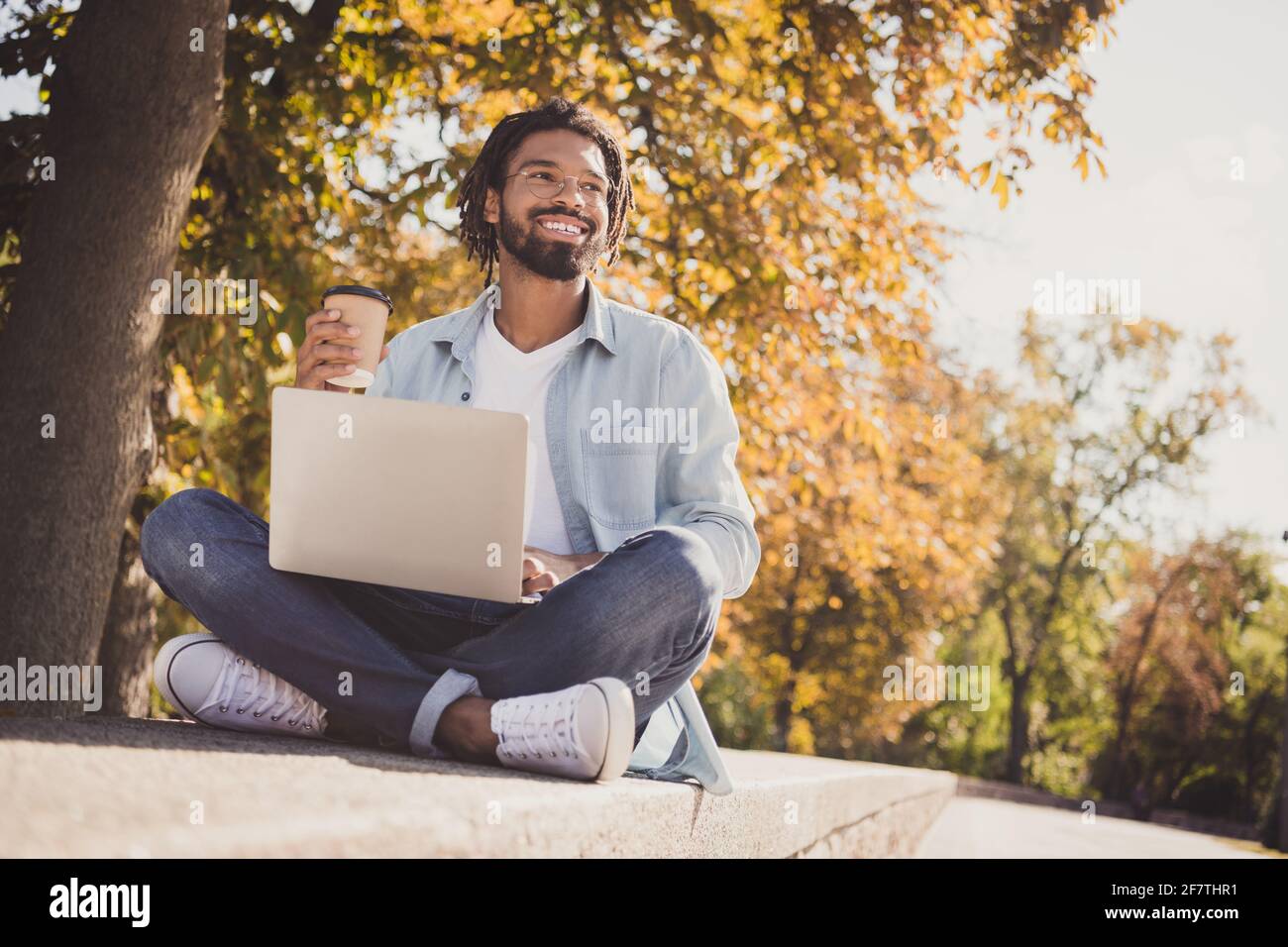 Portrait of handsome cheerful guy travel blogger sitting concrete ...