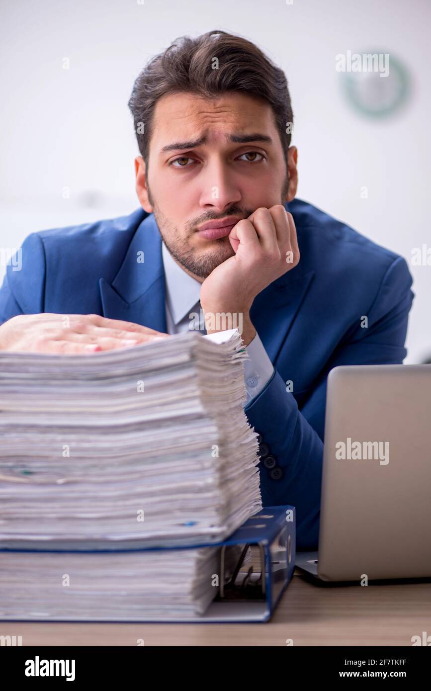 Young male employee and too much work in the office Stock Photo - Alamy