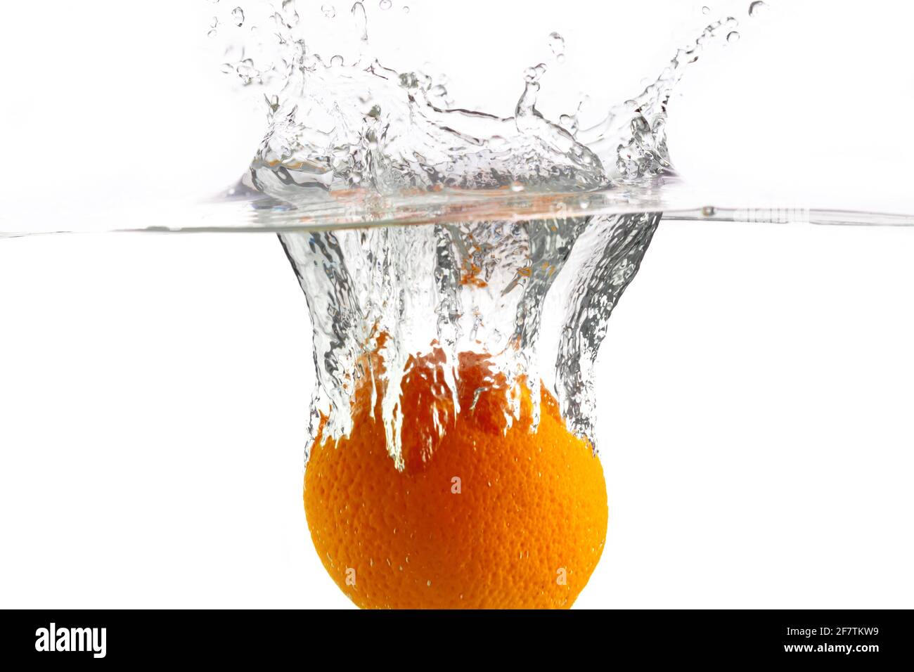 one ripe juicy orange falls into the water with splashes on a white ...
