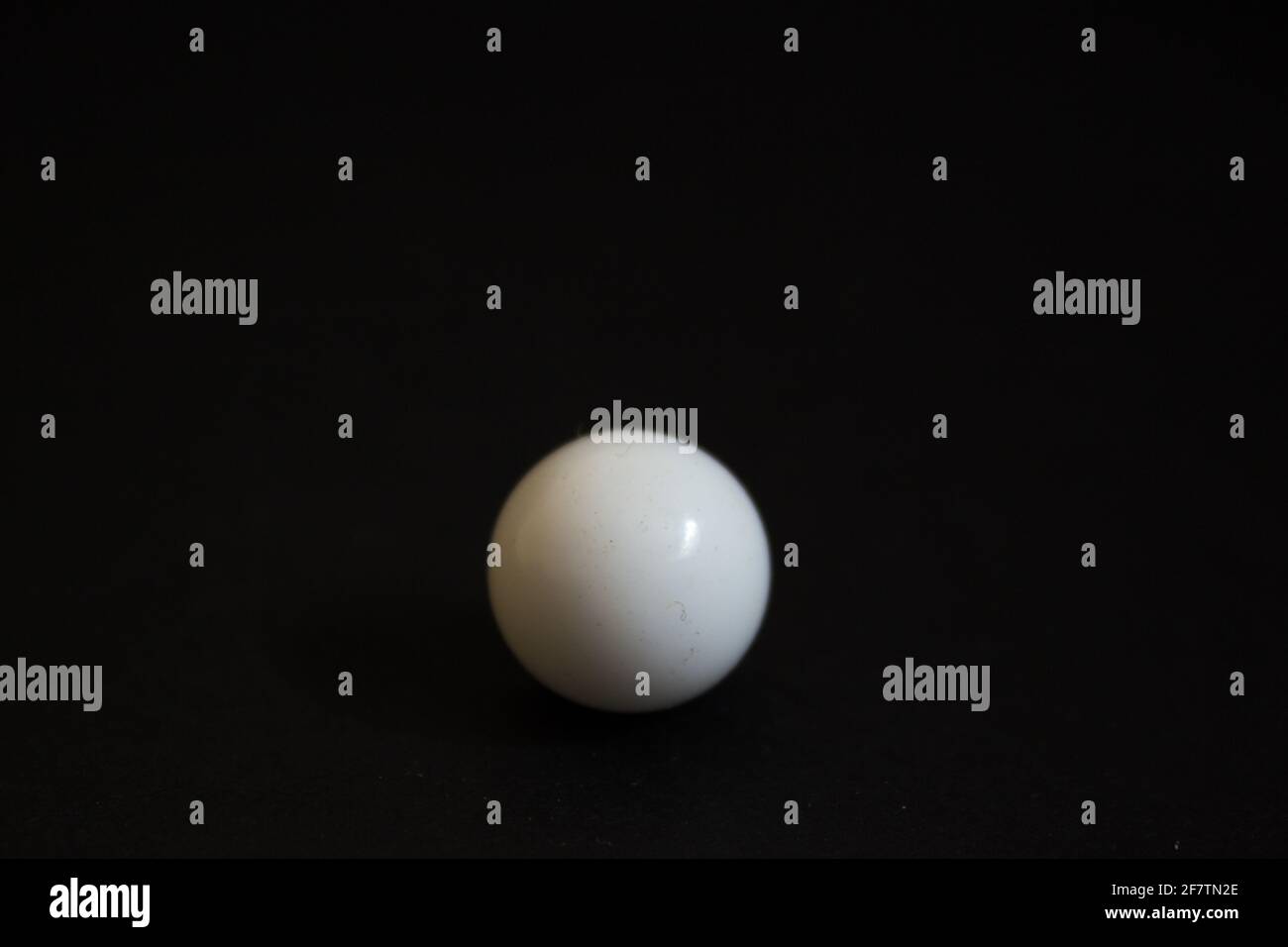 Closeup shot of a single white marble ball isolated on black background ...