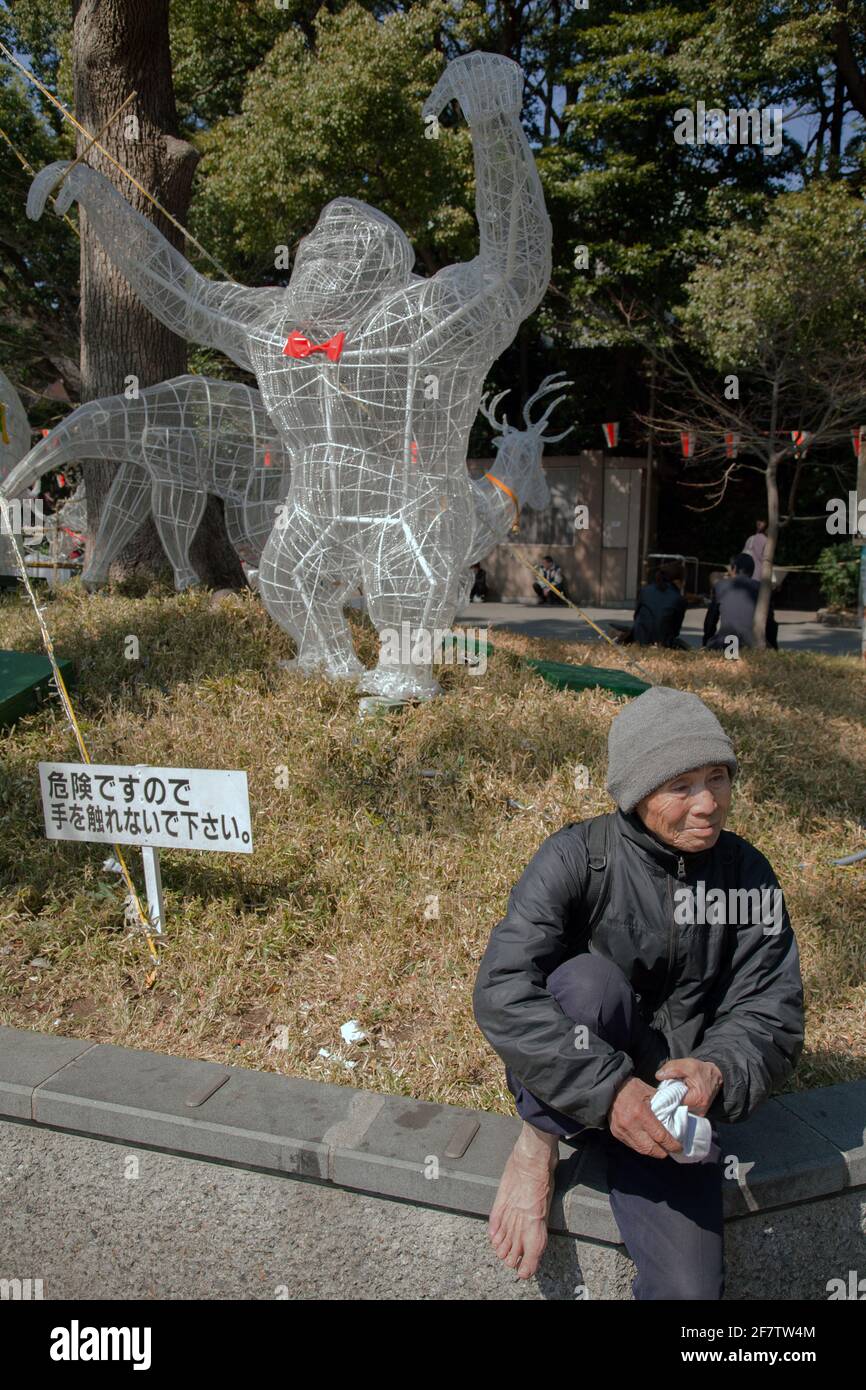 Japanese homeless man seated on wall in Ueno Park in front of large ...