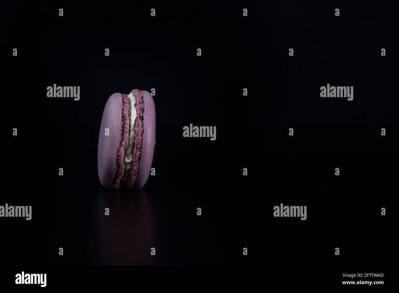 Purple macaron isolated on black background Stock Photo - Alamy