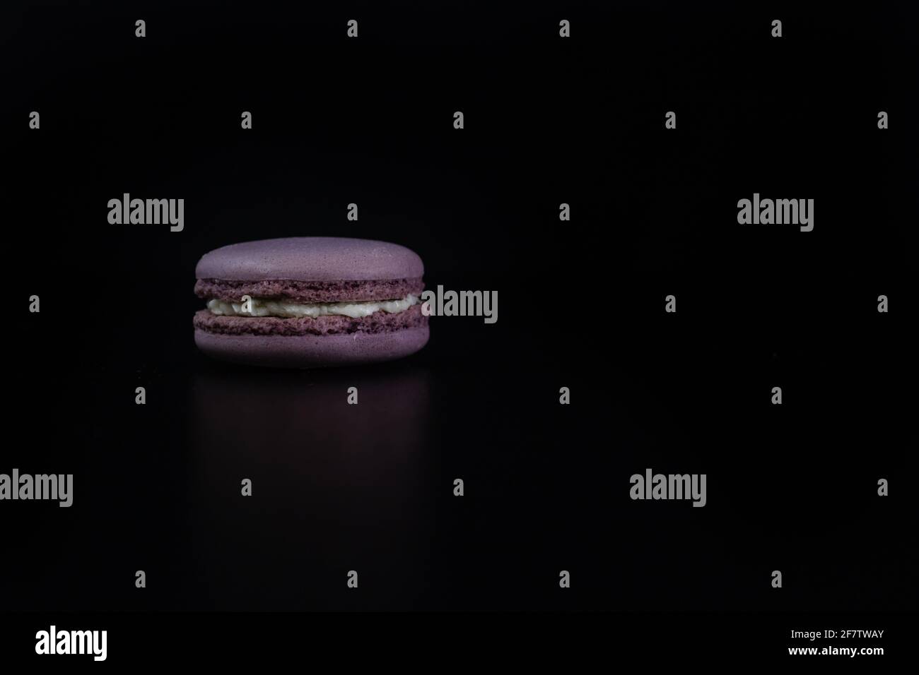 Purple macaron isolated on black background Stock Photo - Alamy