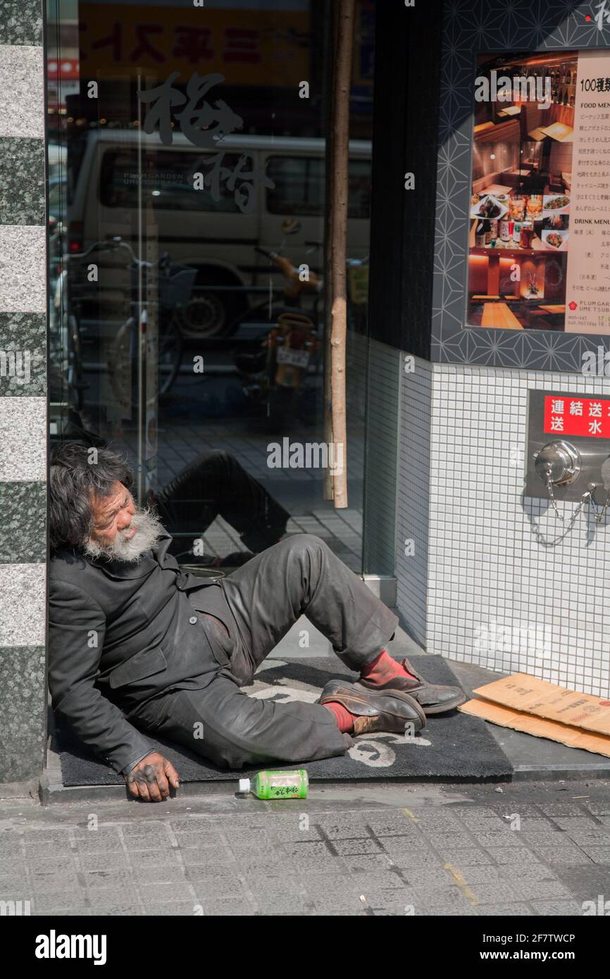 Homeless Japanese male seated on ground in Japanese restaurant doorway ...