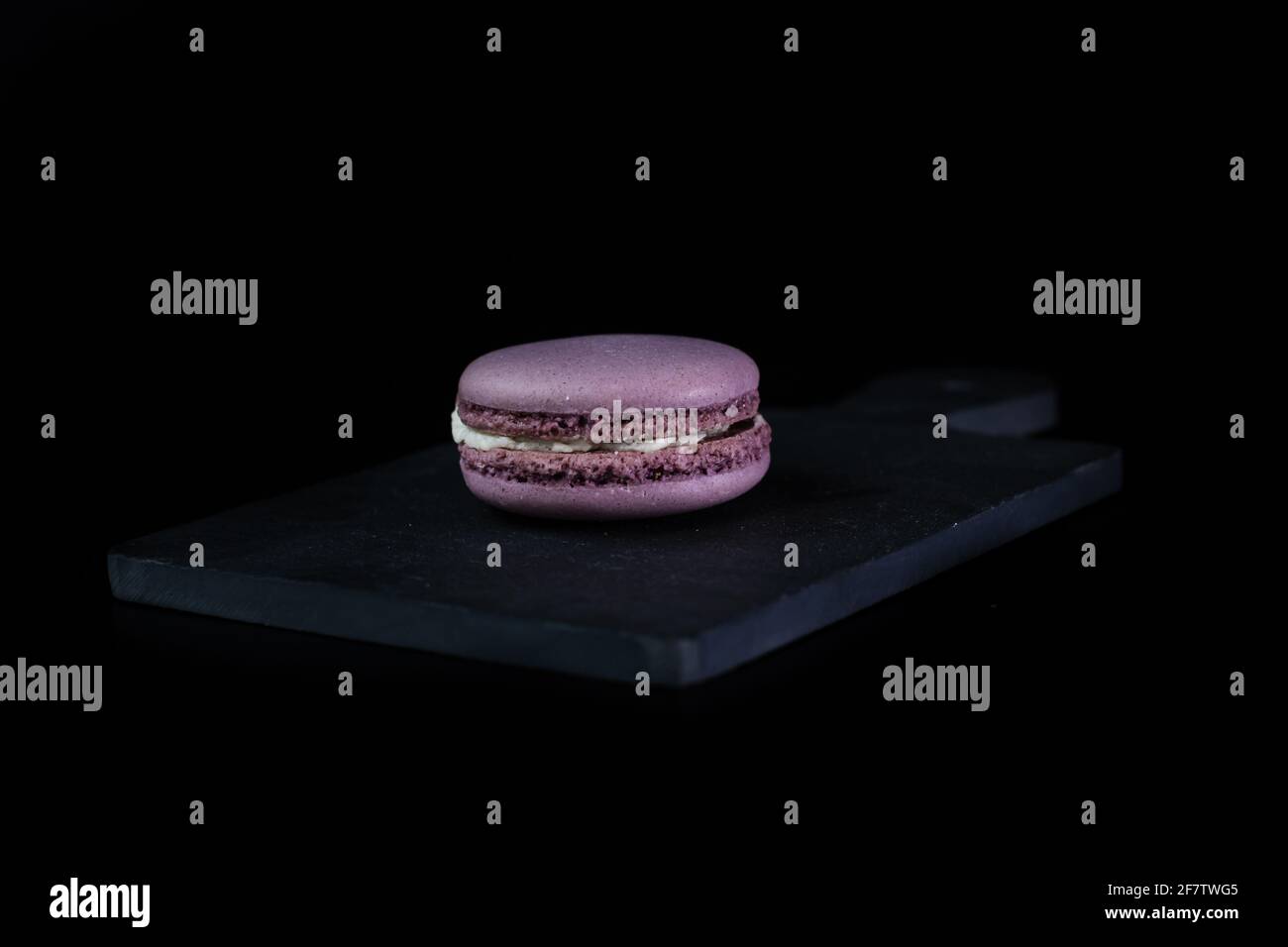 Purple macaron on blue board isolated on black background Stock Photo ...