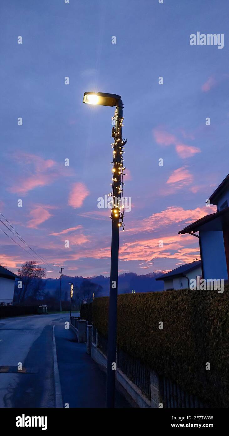 Closeup of lamp post covered with Christmas lights against a beautiful ...